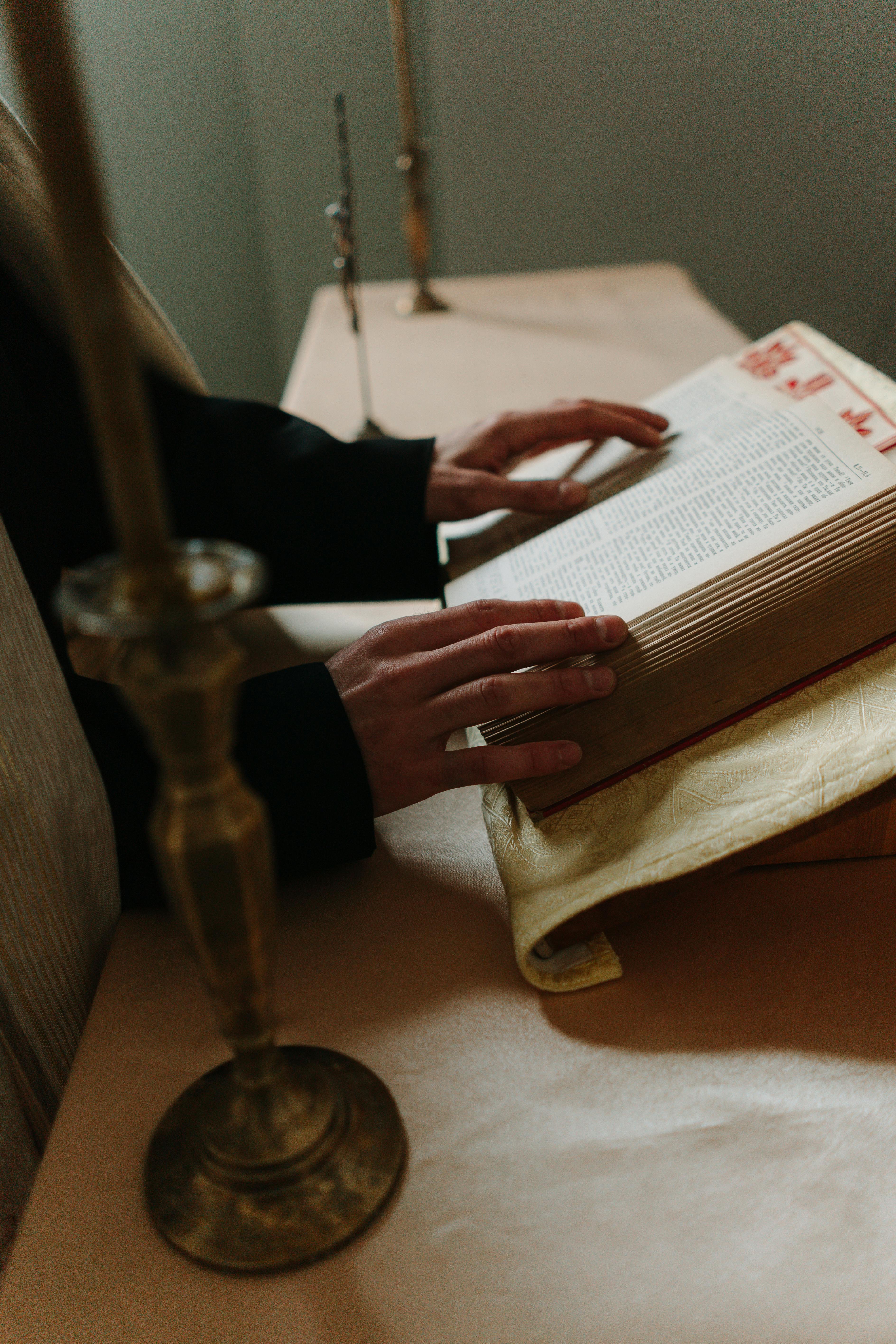 Priest Standing Behind the Altar Table with a Bible · Free Stock Photo