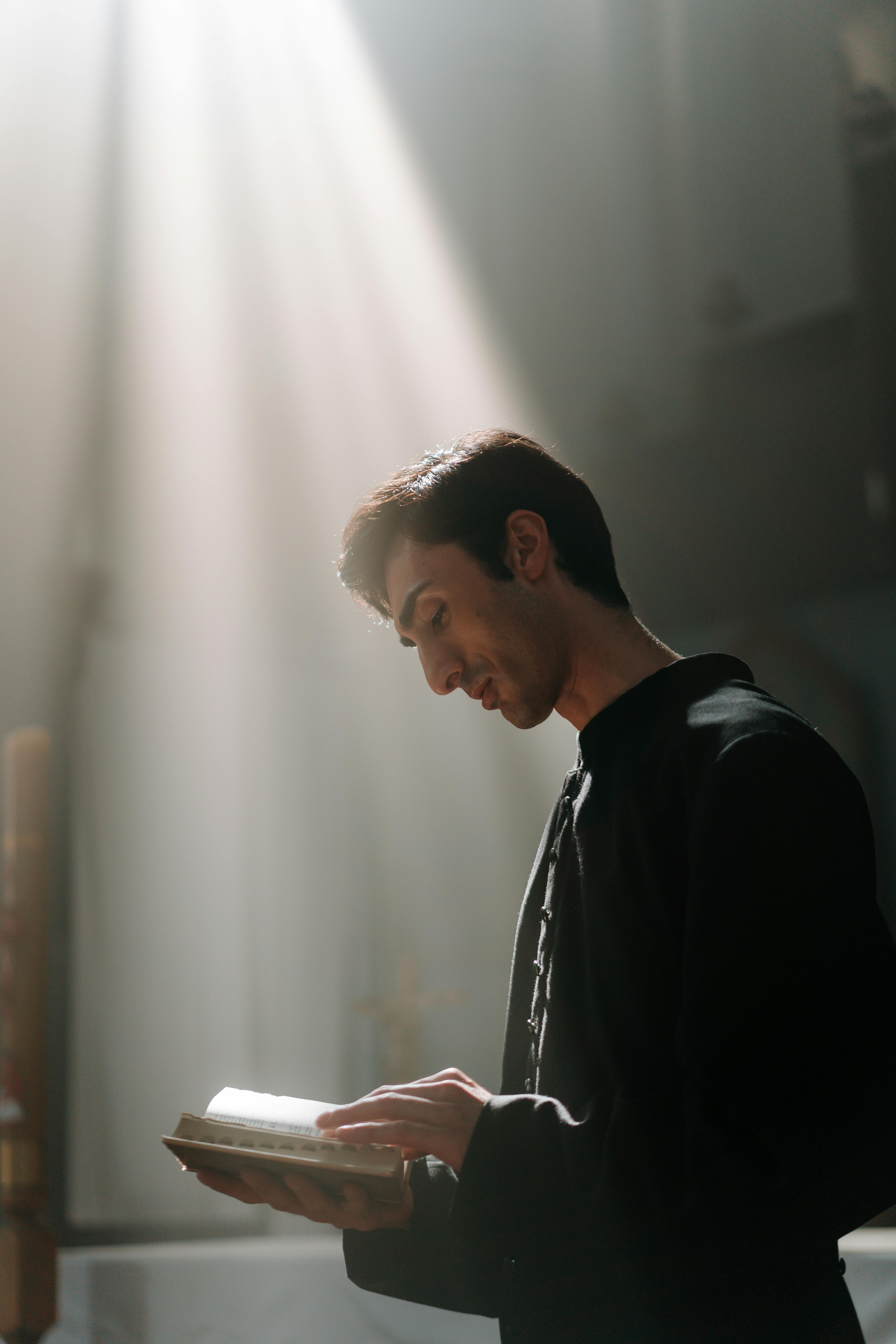 A Low Angle Shot of a Priest Reading Bible · Free Stock Photo