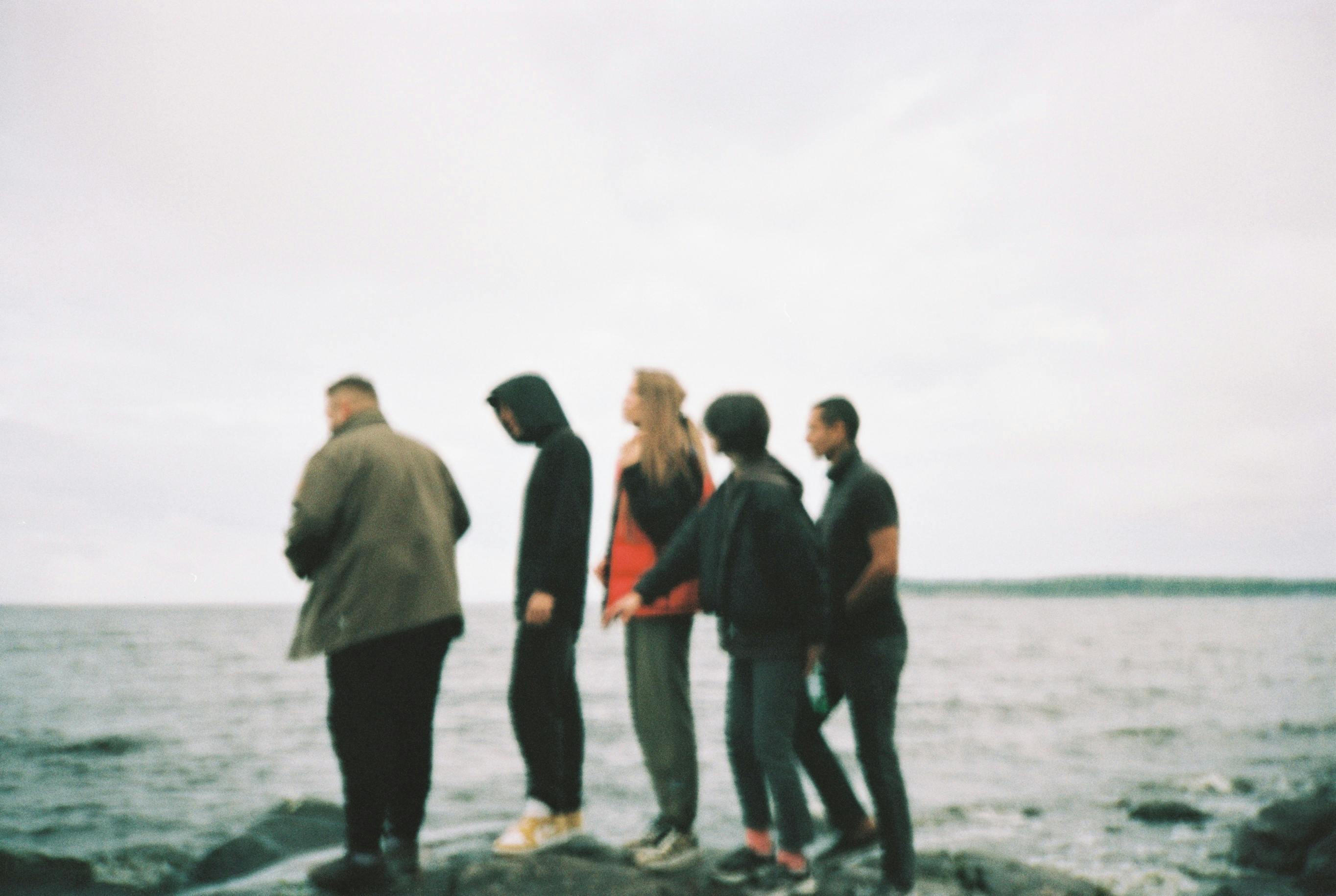 A Group of People Wearing Jackets Walking Together on Pavement · Free ...