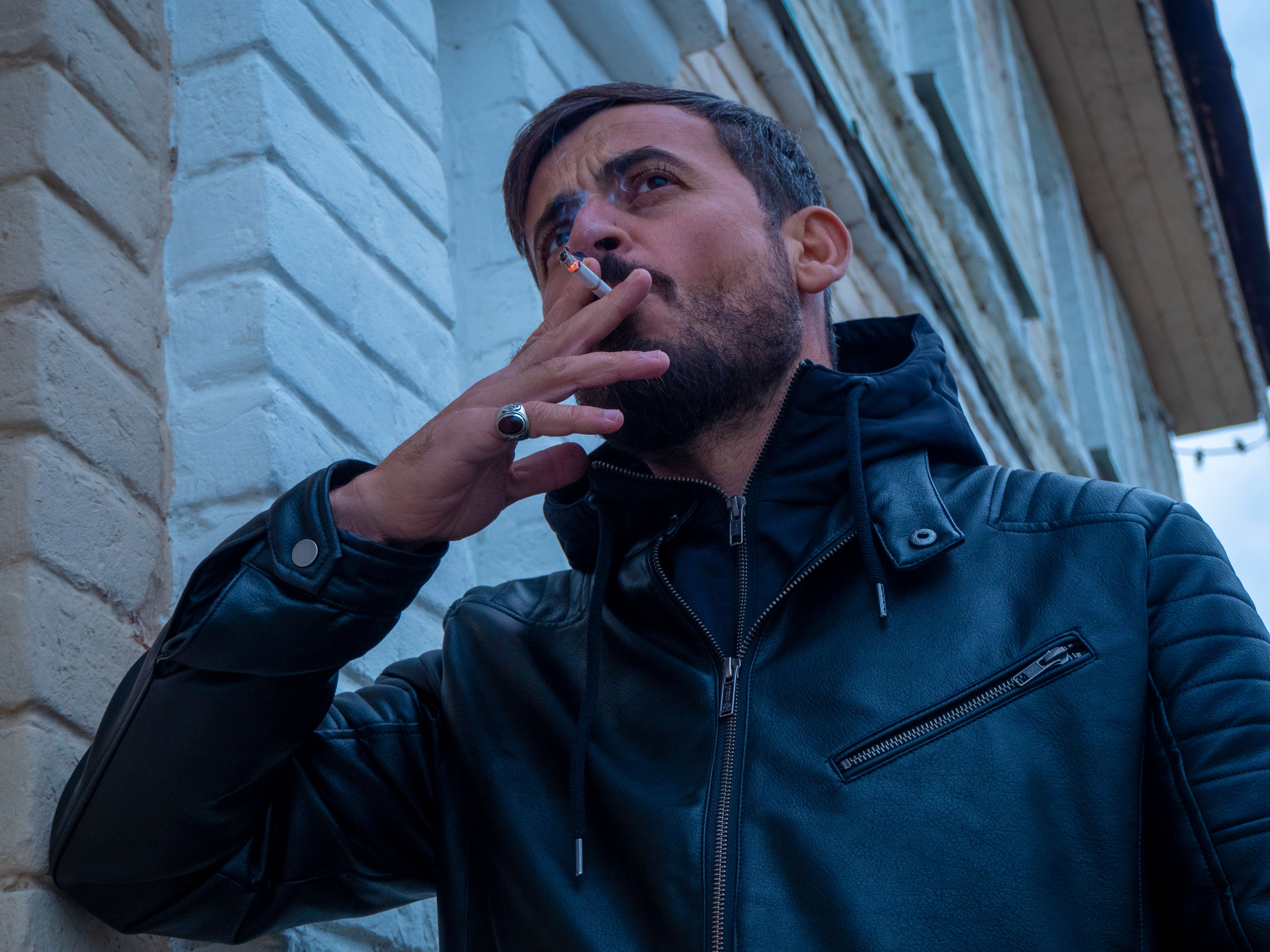 Low-Angle Shot of a Man in Leather Jacket Smoking · Free Stock Photo