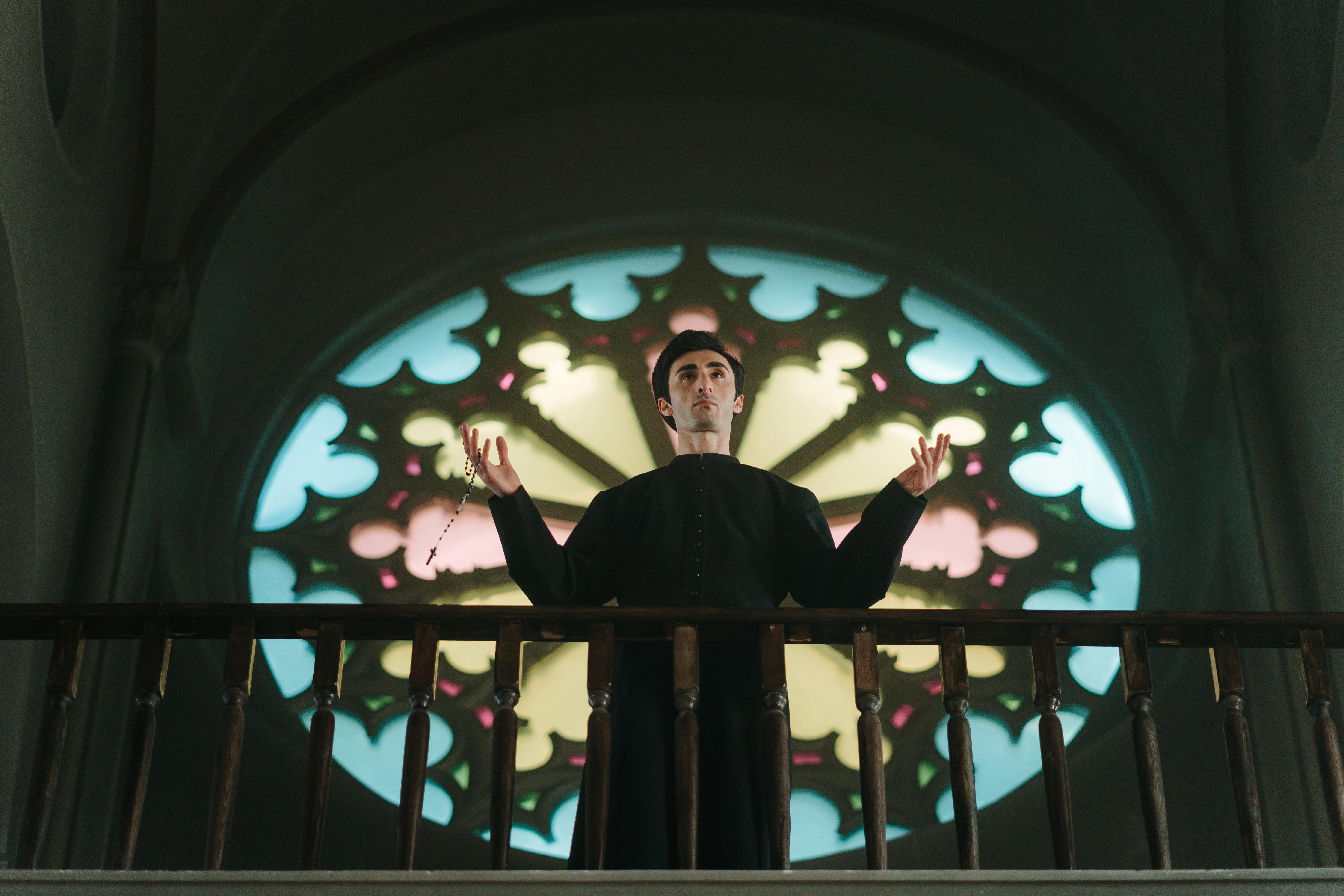 Priest with a Rosary in his Hand Praying with his Hands Raised · Free ...