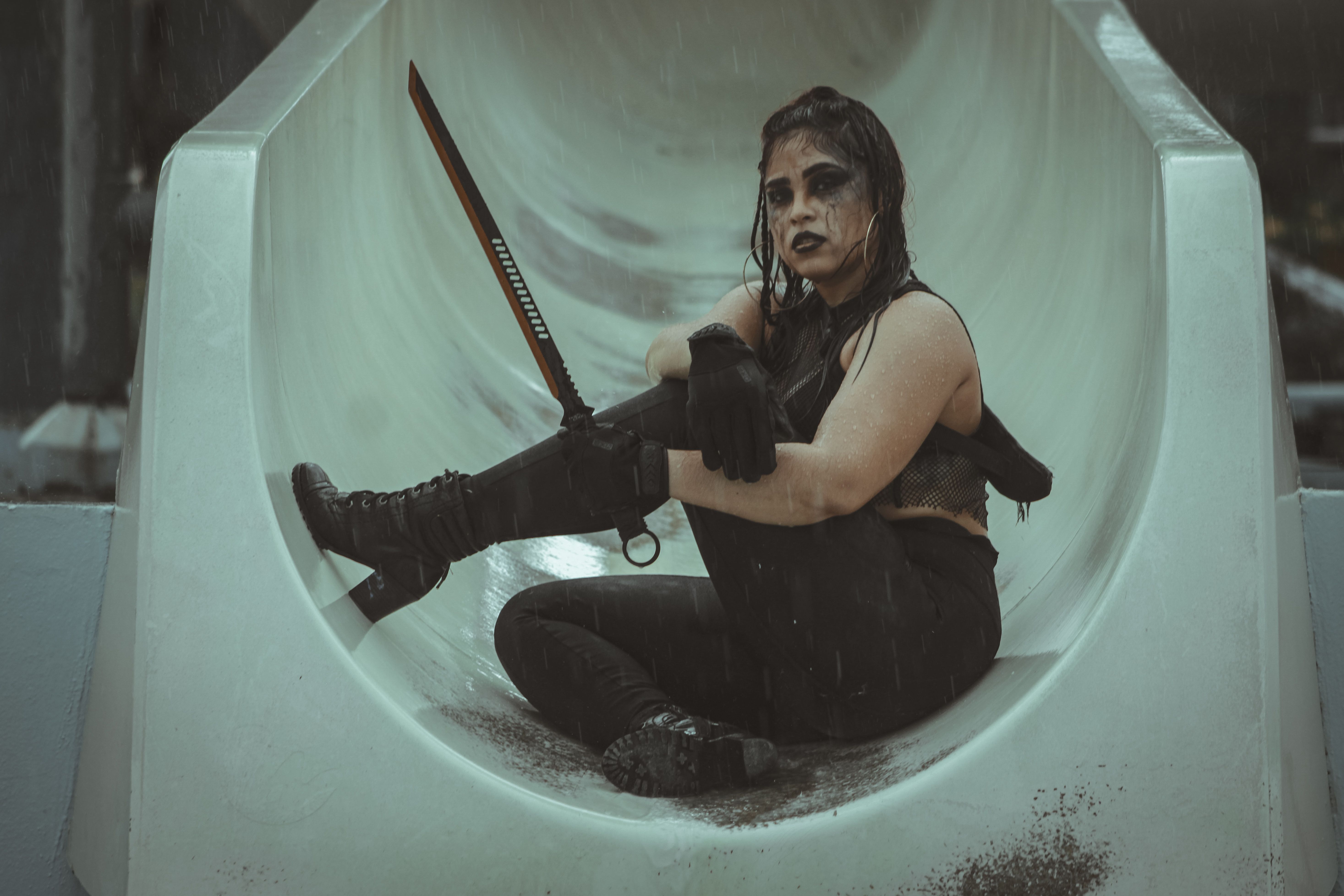 Woman Sitting on Slide with Sword in Rain · Free Stock Photo