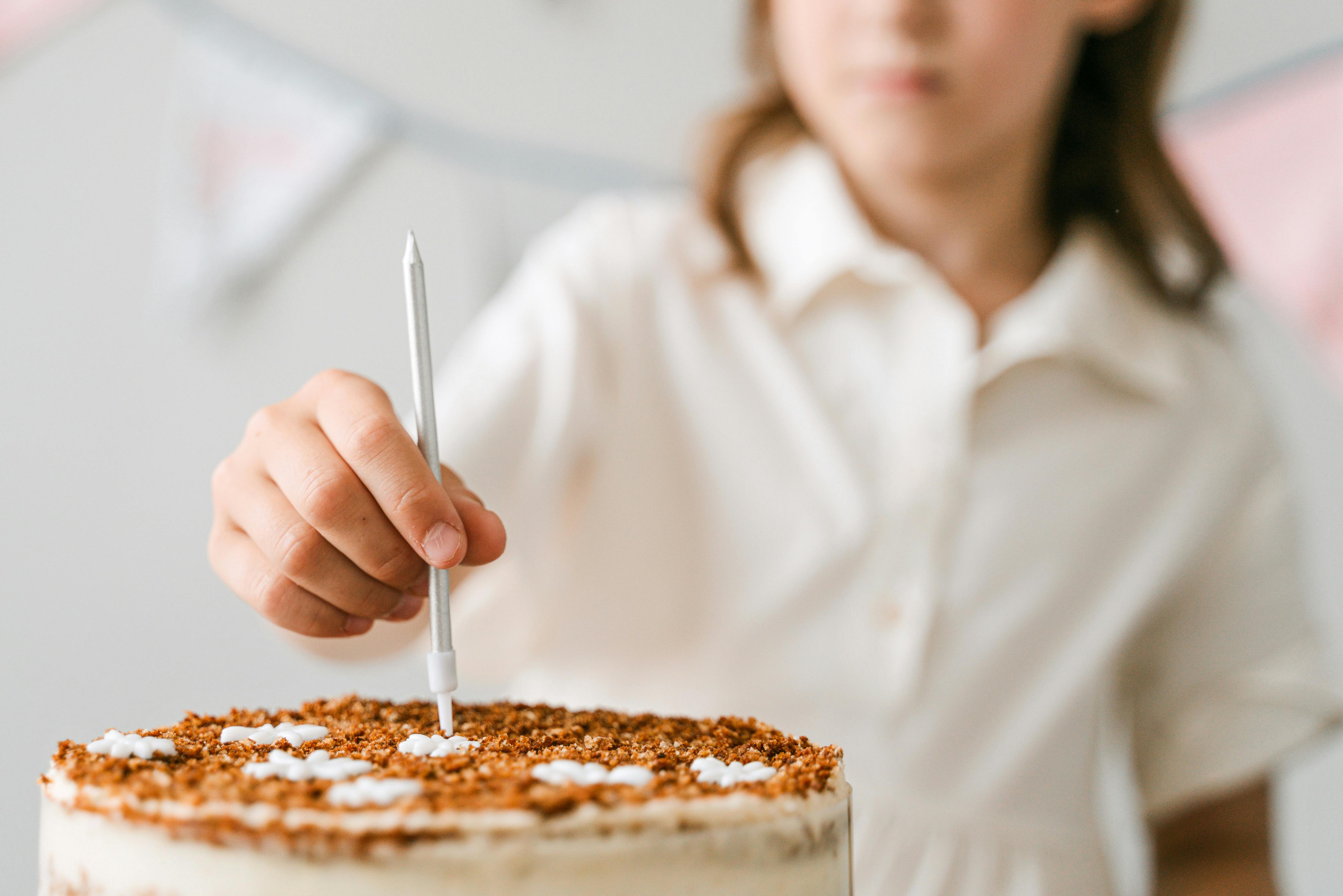 A Girl Putting a Candle on a Birthday Cake · Free Stock Photo