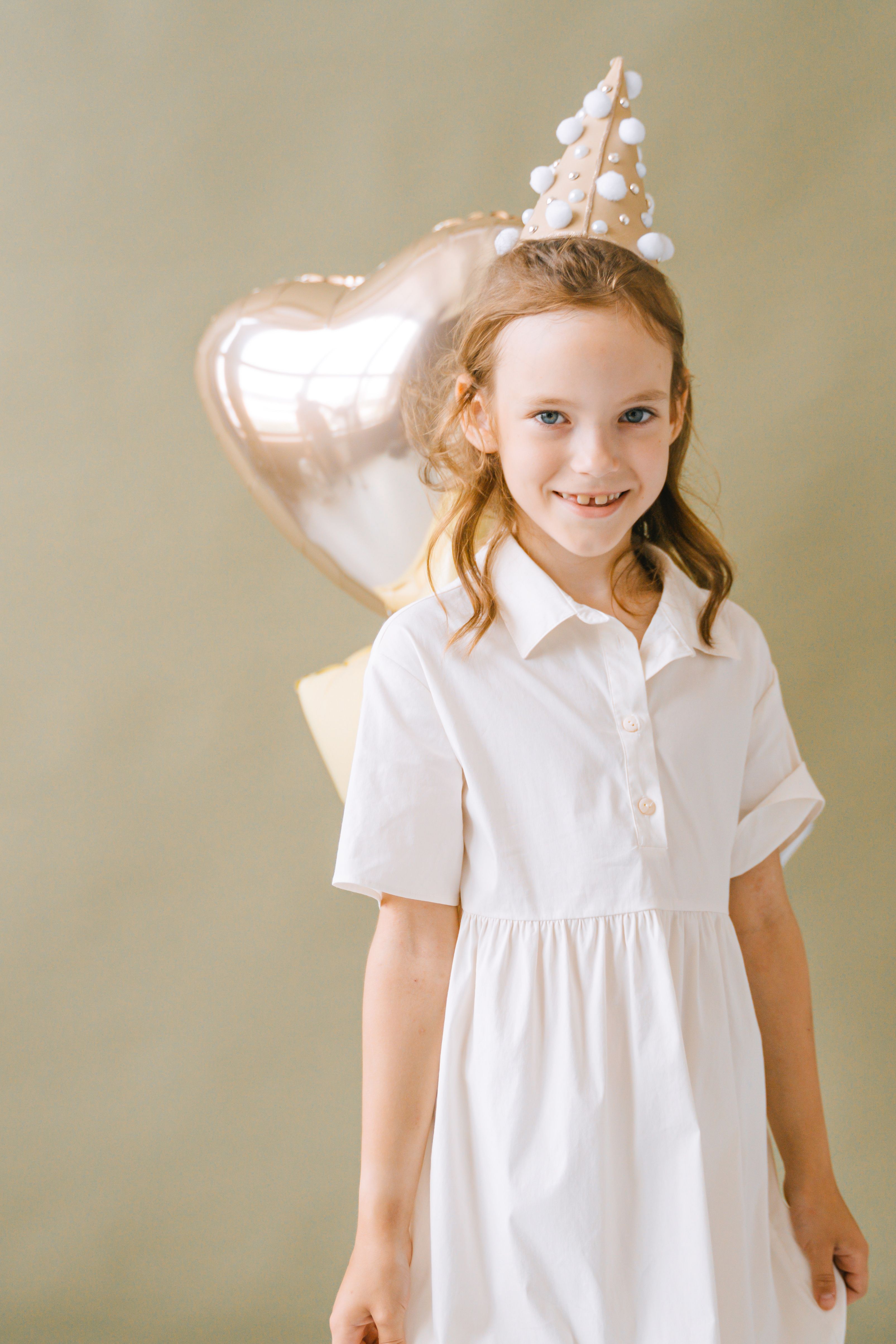 Kid in White Dress Wearing a Party Hat · Free Stock Photo