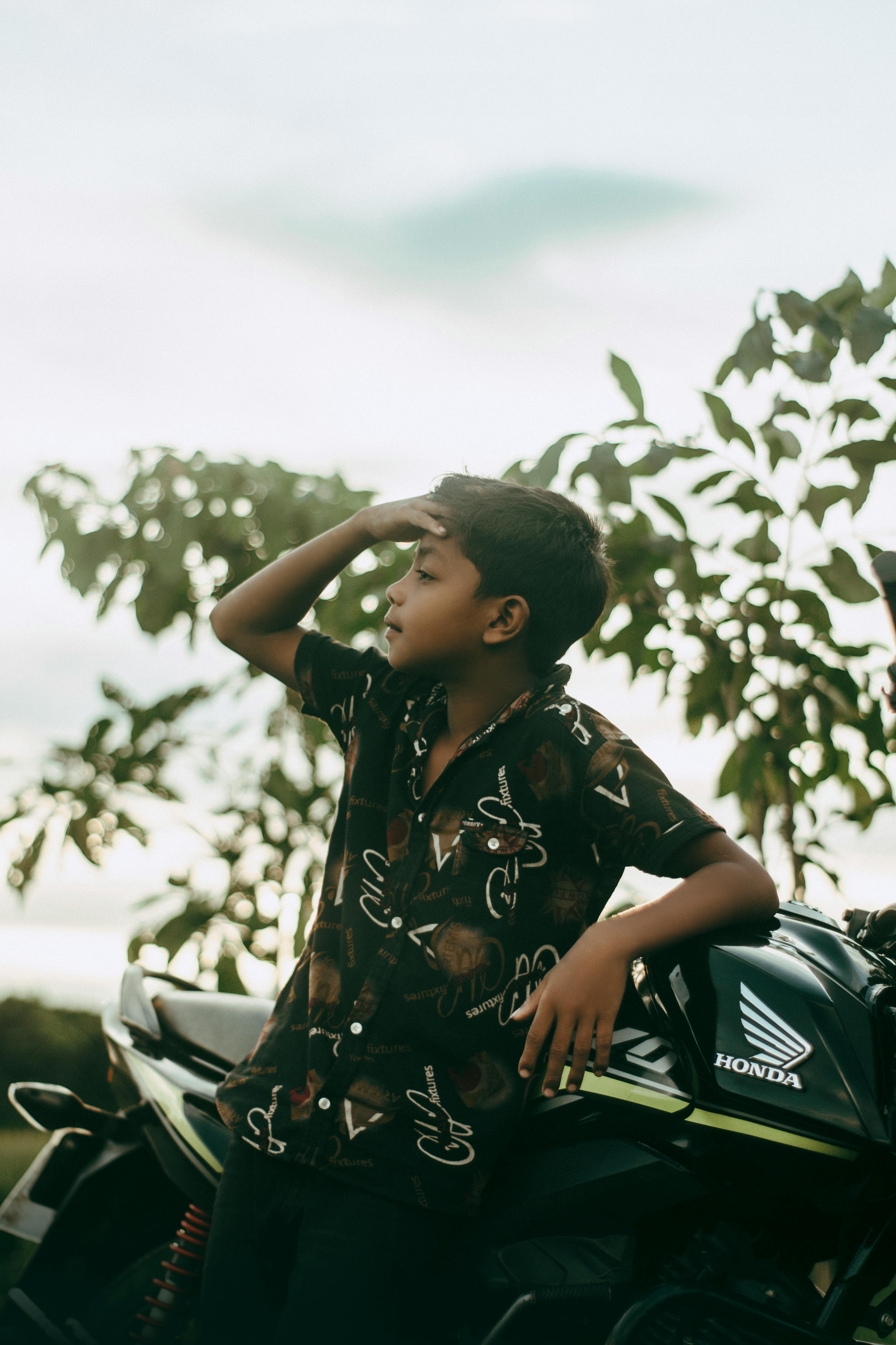 Photo of a Boy in an Orange Shirt Riding a Motorcycle · Free Stock Photo