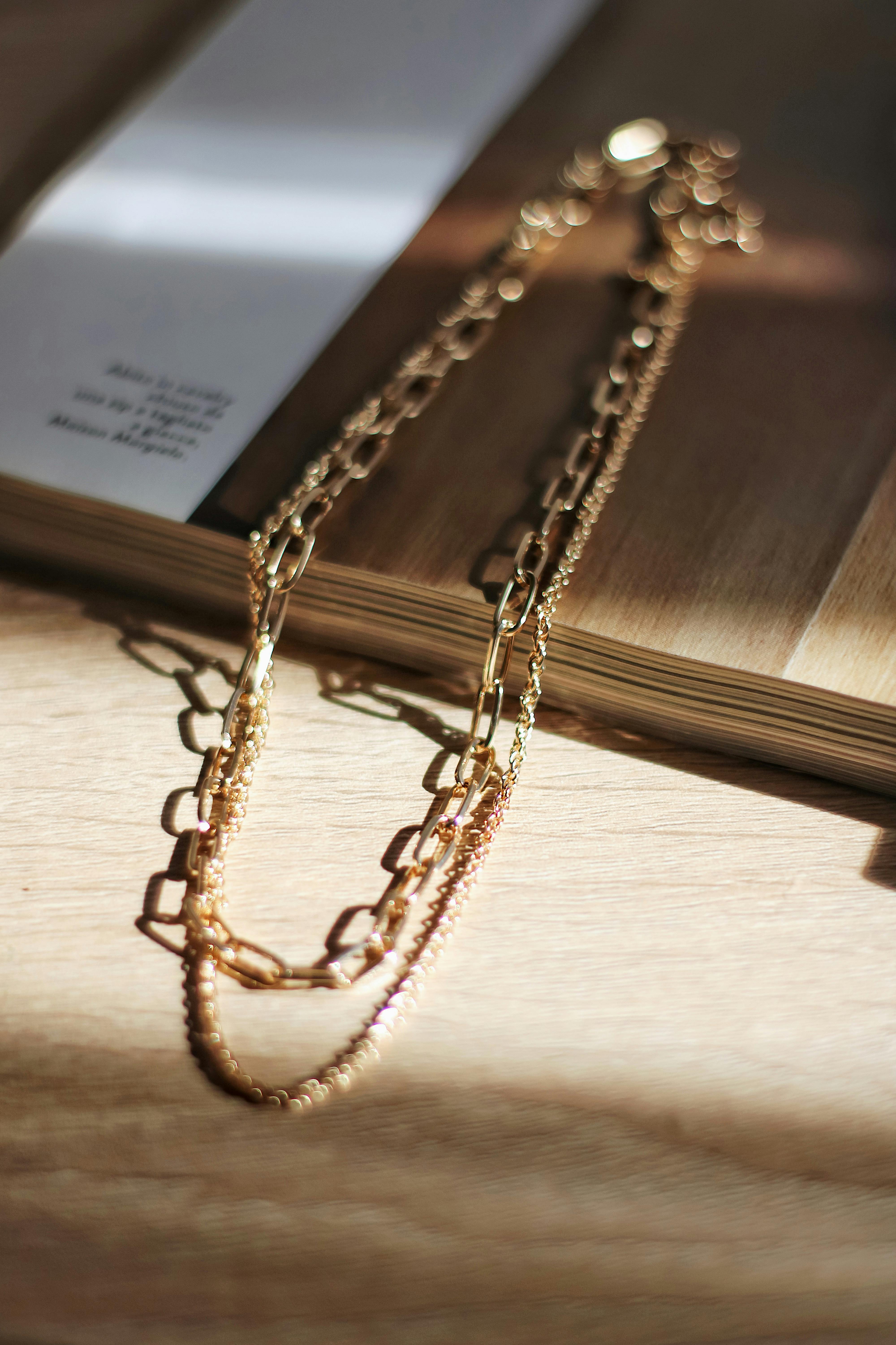 Gold Chain Necklace on Brown Wooden Table · Free Stock Photo