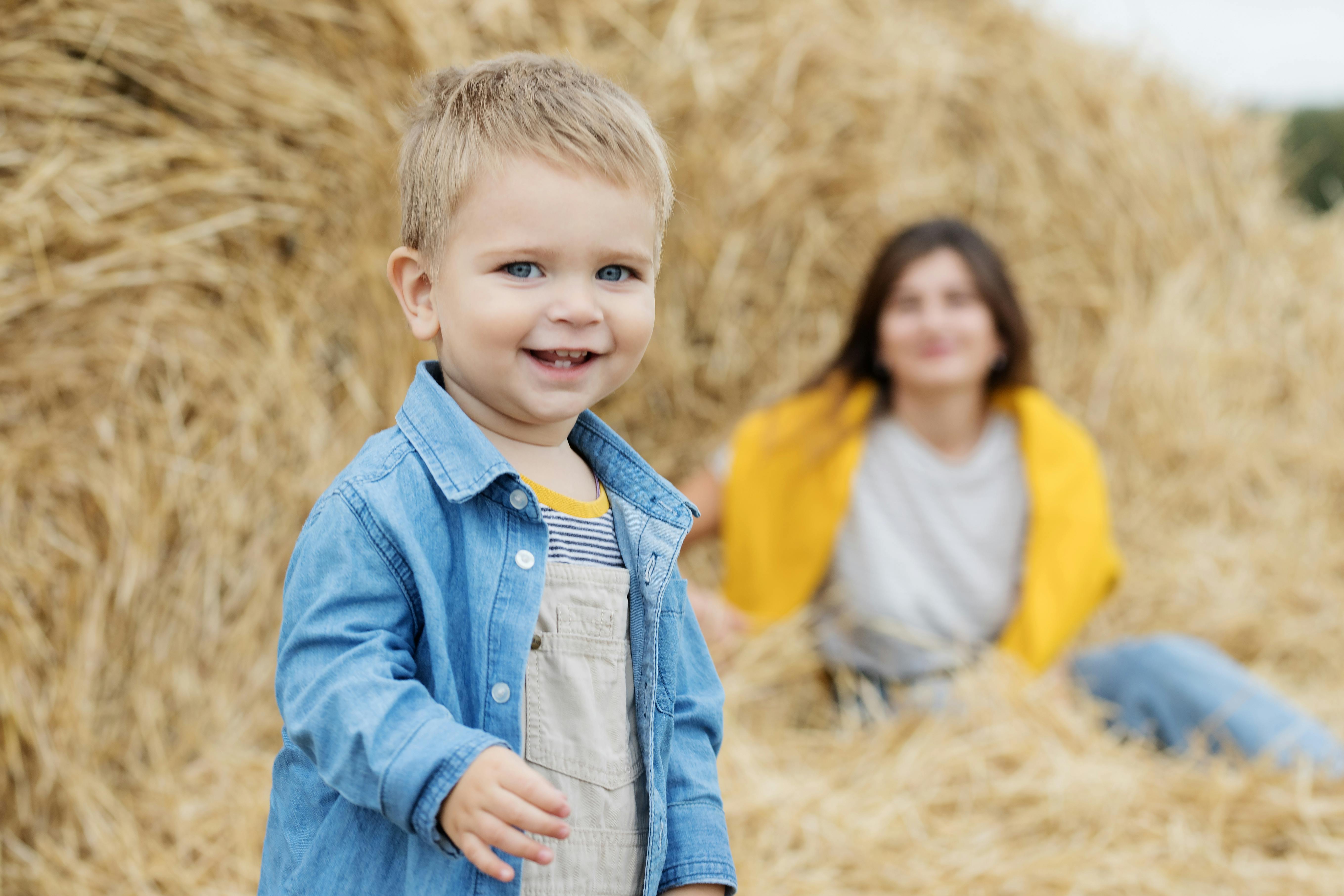 Little Smiling Boy Next to a Haystack · Free Stock Photo