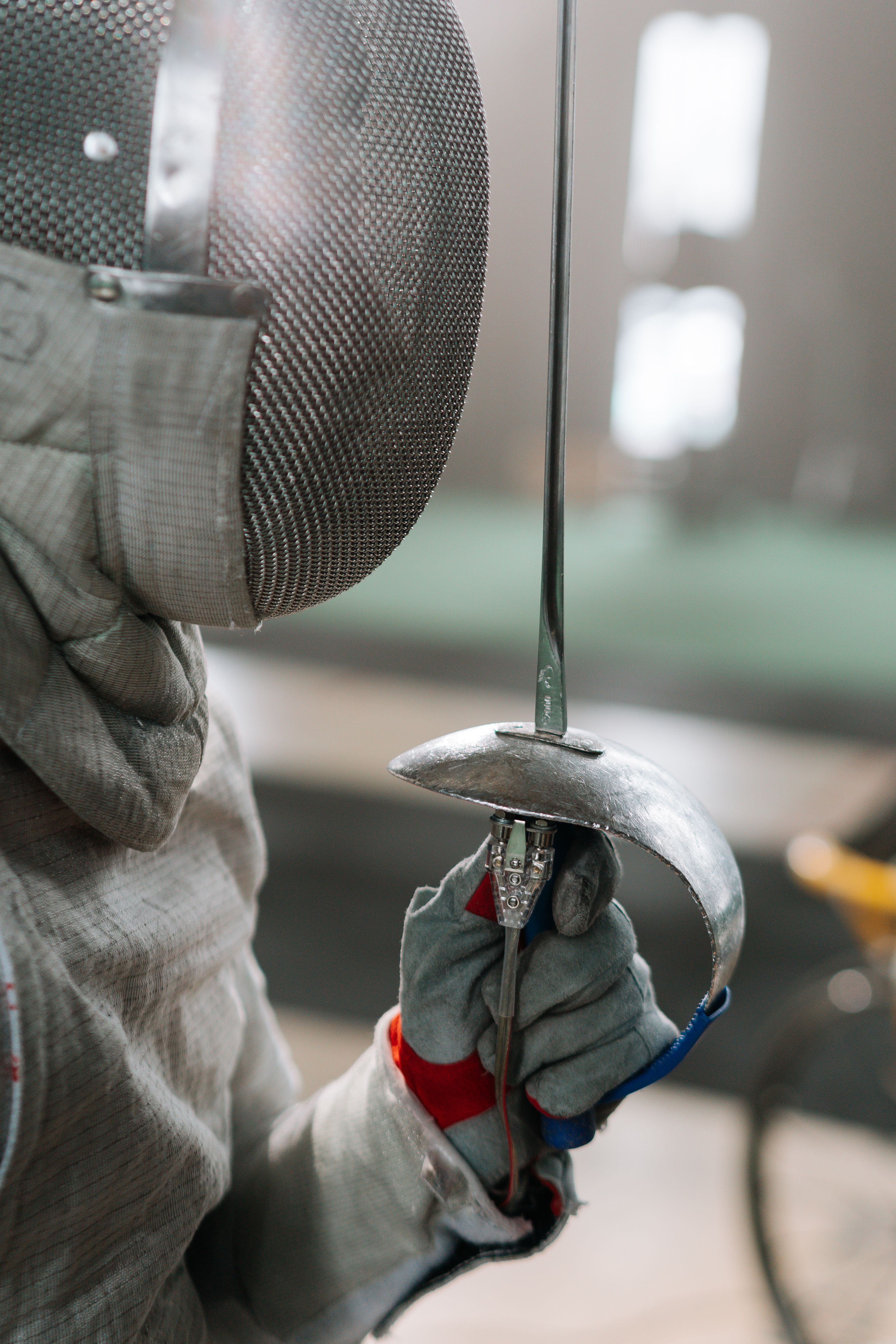 A side view on an athlete wearing a fencing mask and holding foil ...