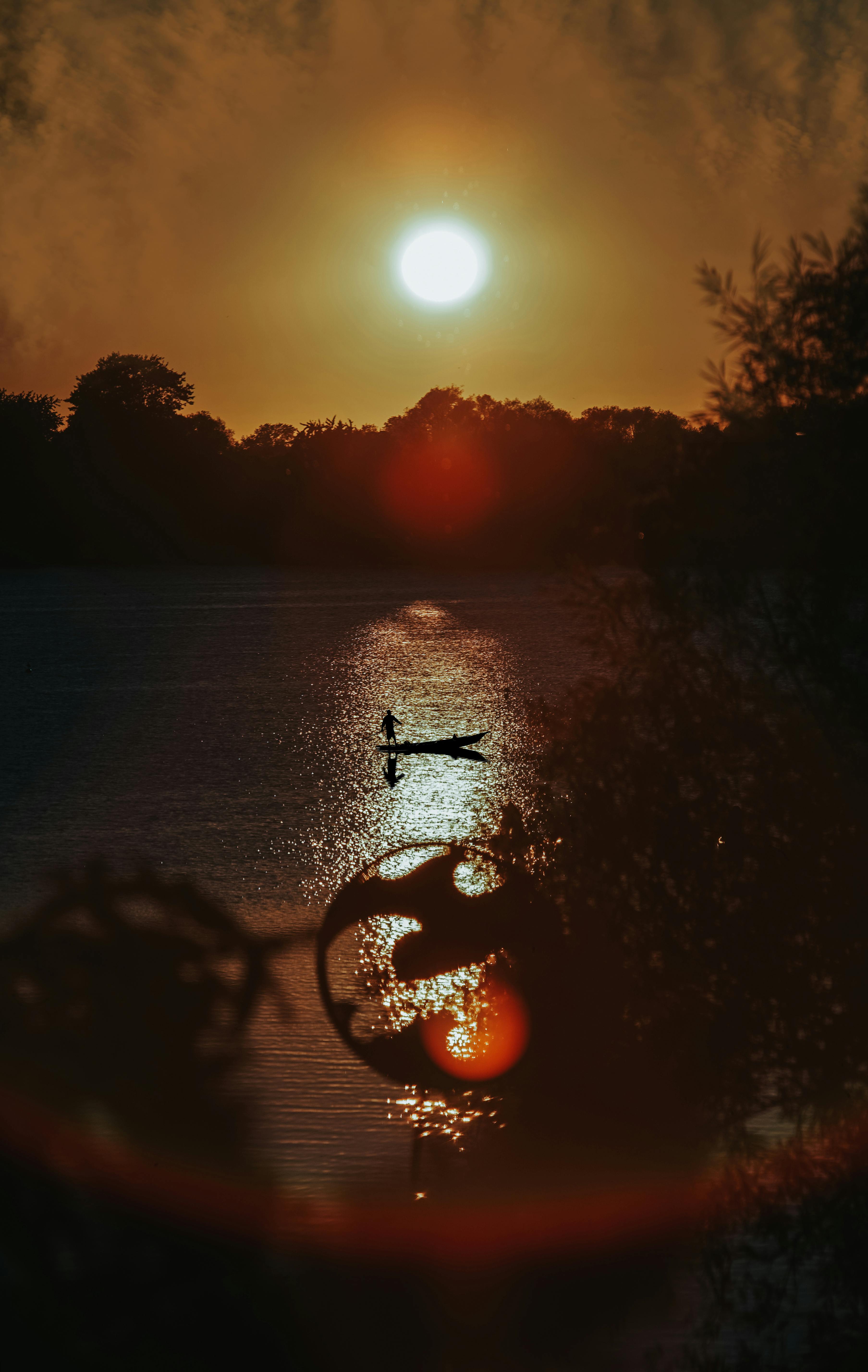 A Sun Setting Over Lake Near Silhouetted Trees · Free Stock Photo