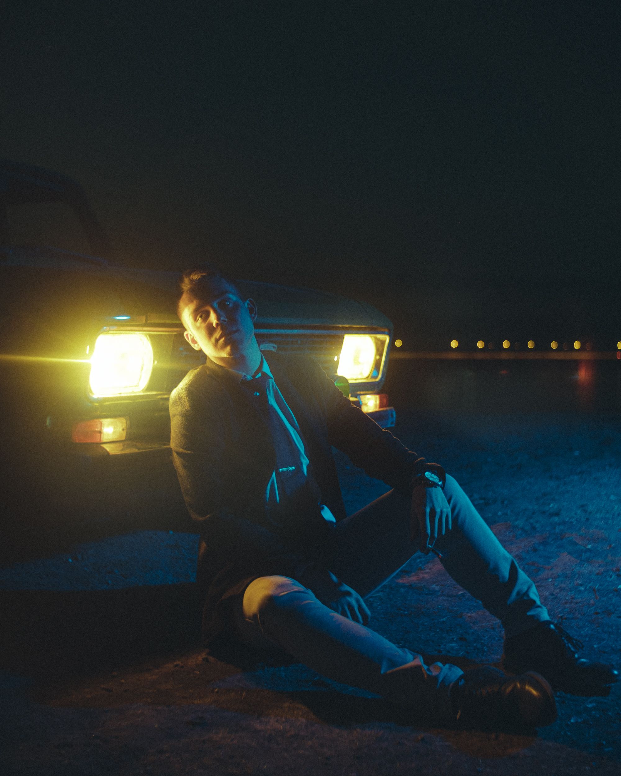 Young man sitting in front of car at night · Free Stock Photo