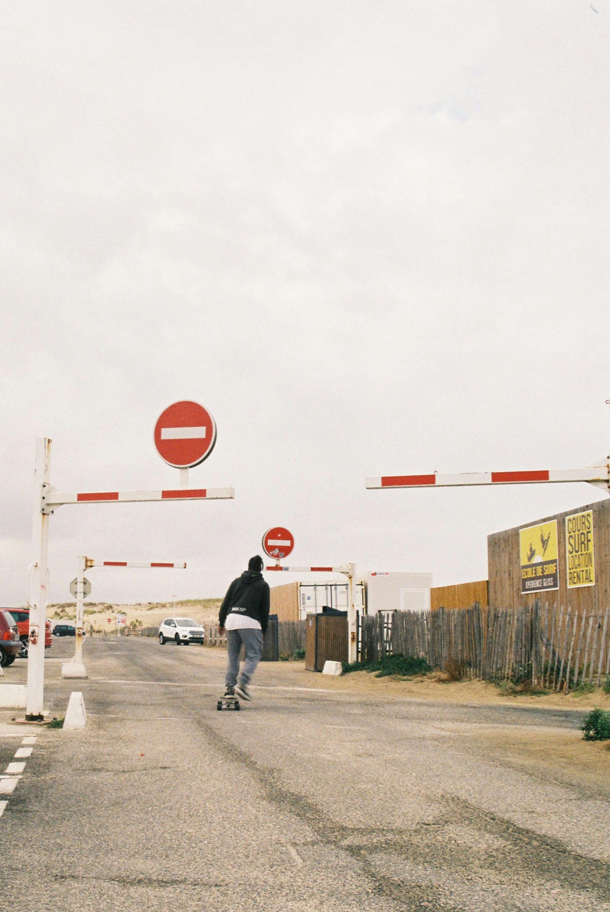 Back View of a Person Skateboarding on Asphalt Road · Free Stock Photo