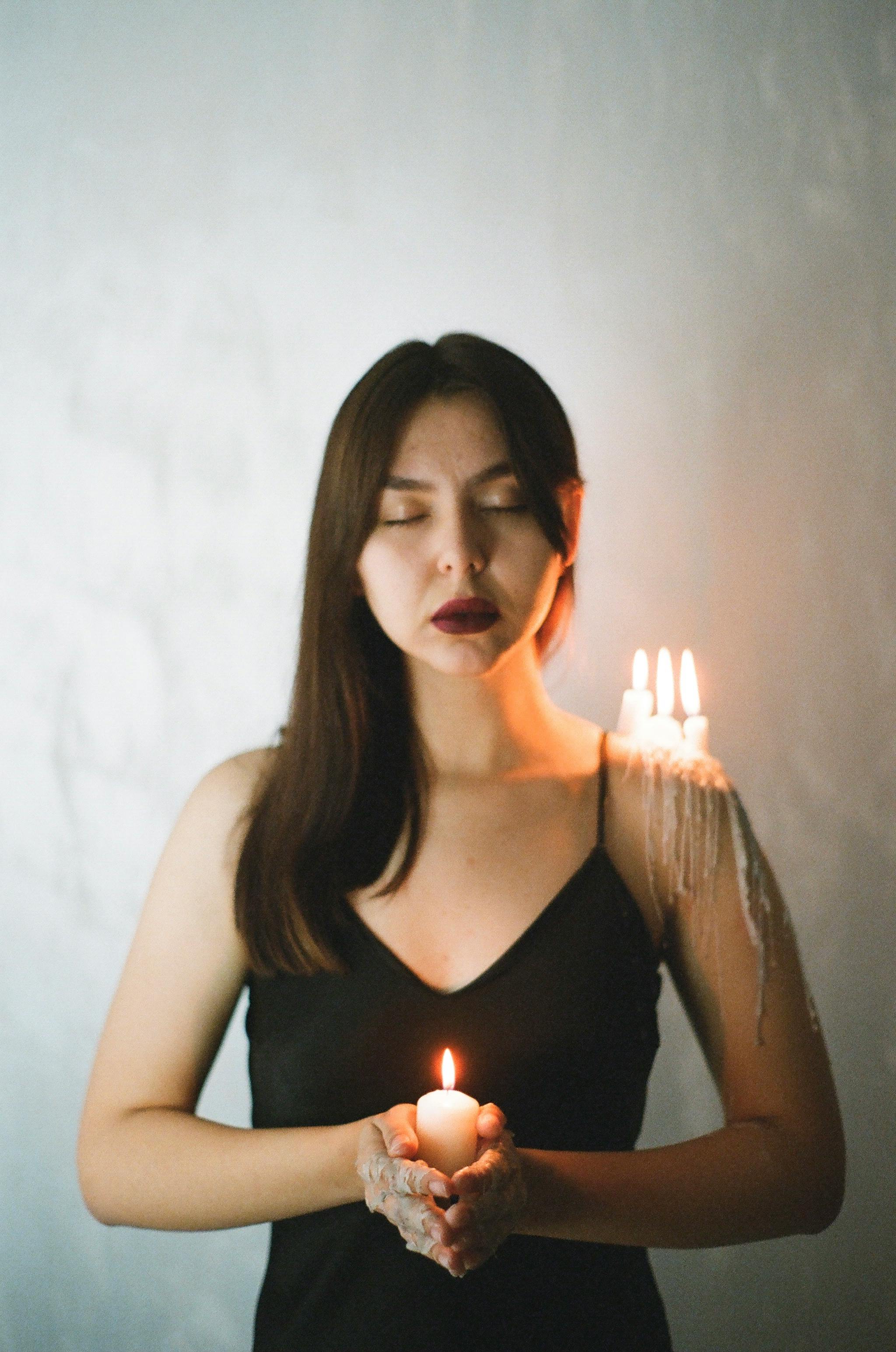 Young woman posing with candle in hands and on shoulder · Free Stock Photo