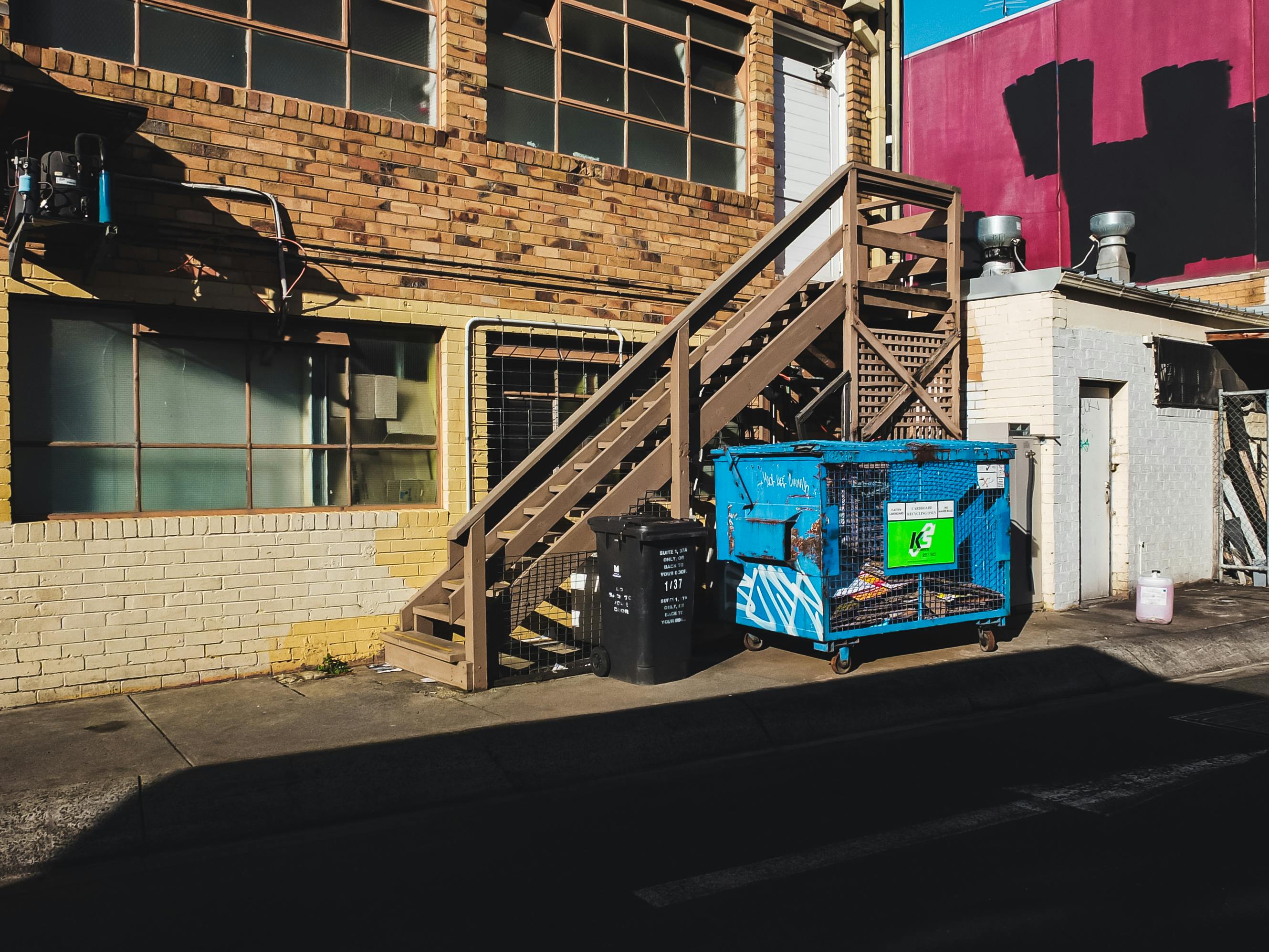 Staircase and Garbage Cans in Front of a Brick Building · Free Stock Photo