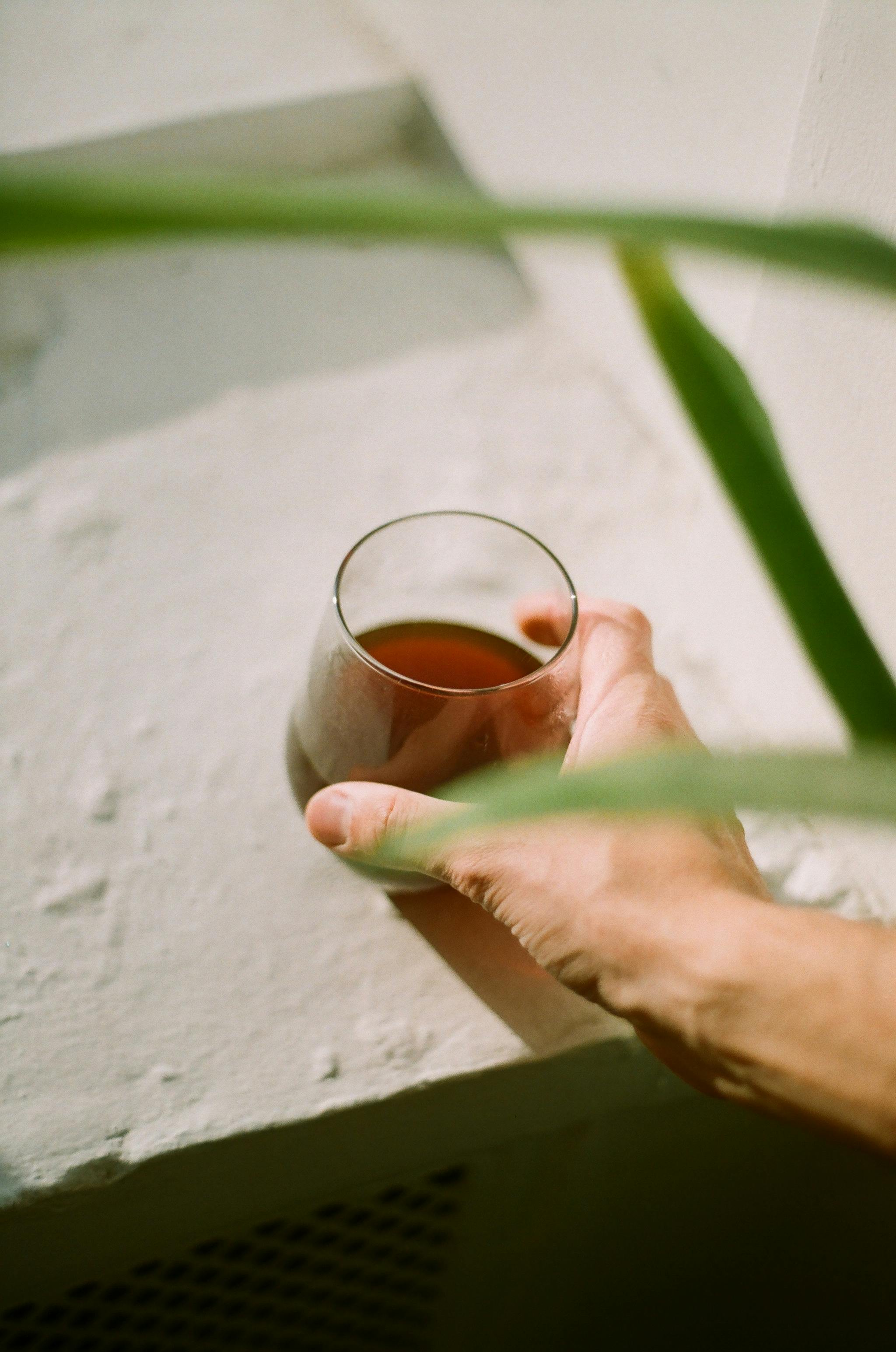 Close up on hand holding glass of tea on wall · Free Stock Photo