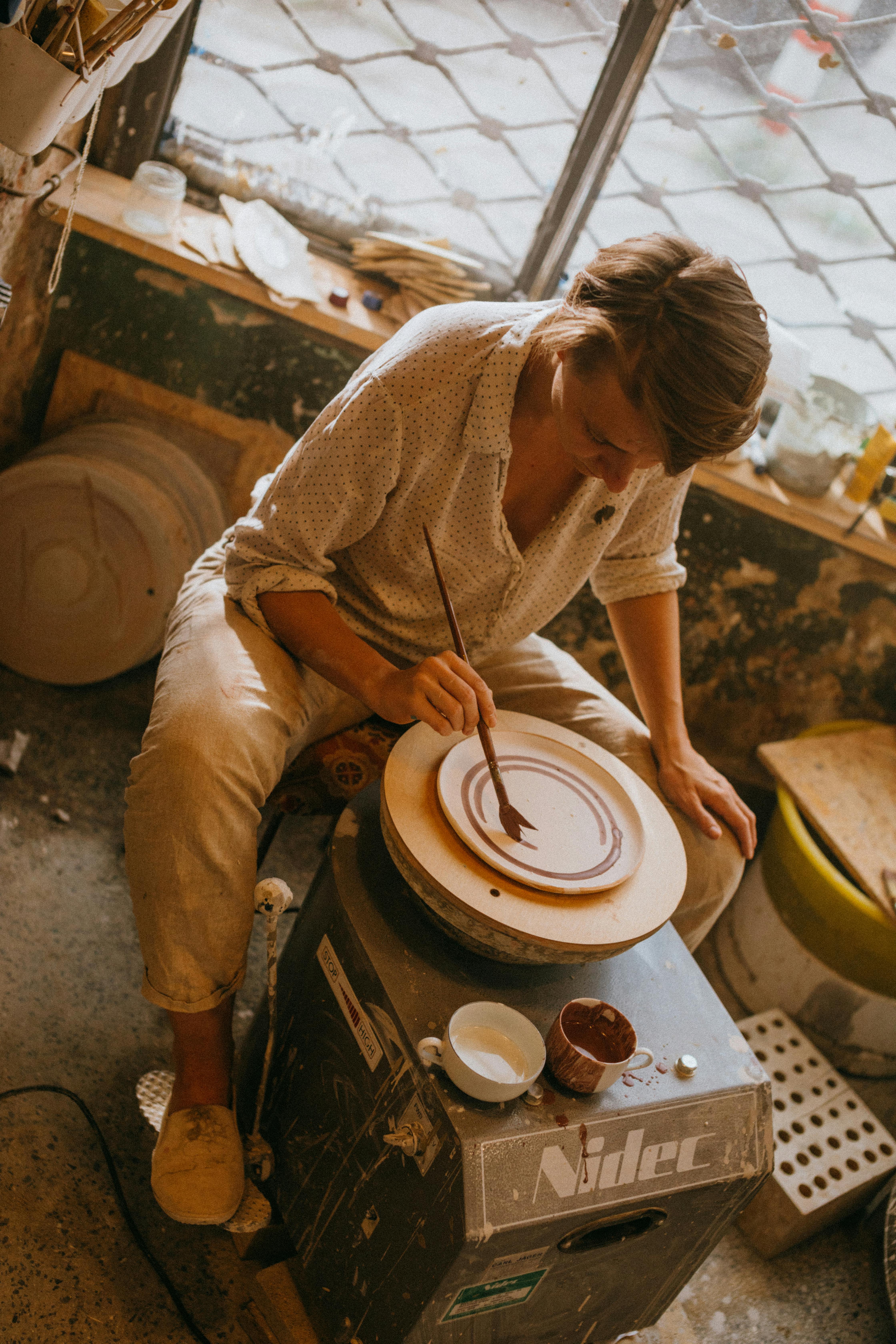 Woman Designing a Round Ceramic Plate · Free Stock Photo