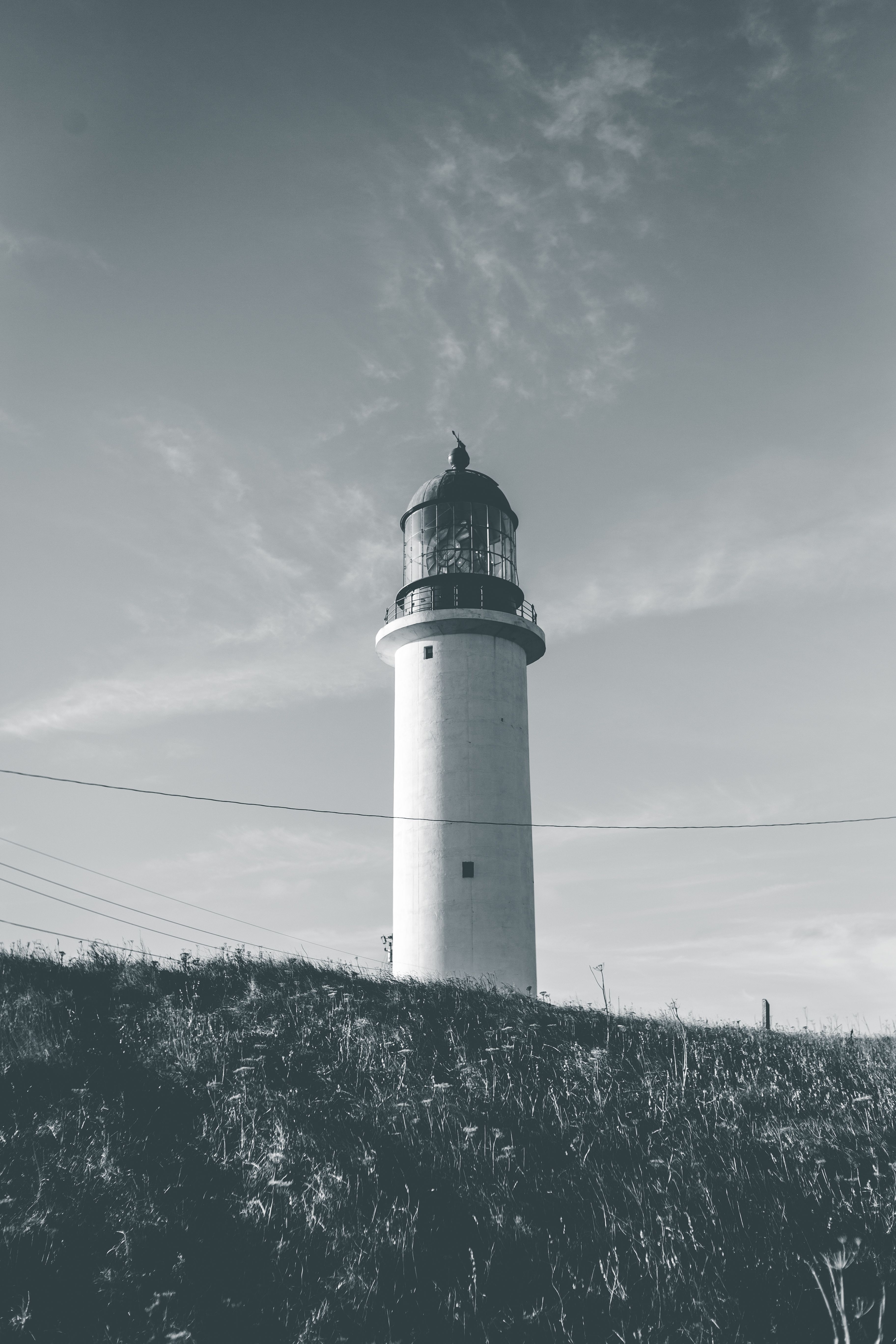 Grayscale Photo of a Lighthouse on a Grassy Field · Free Stock Photo