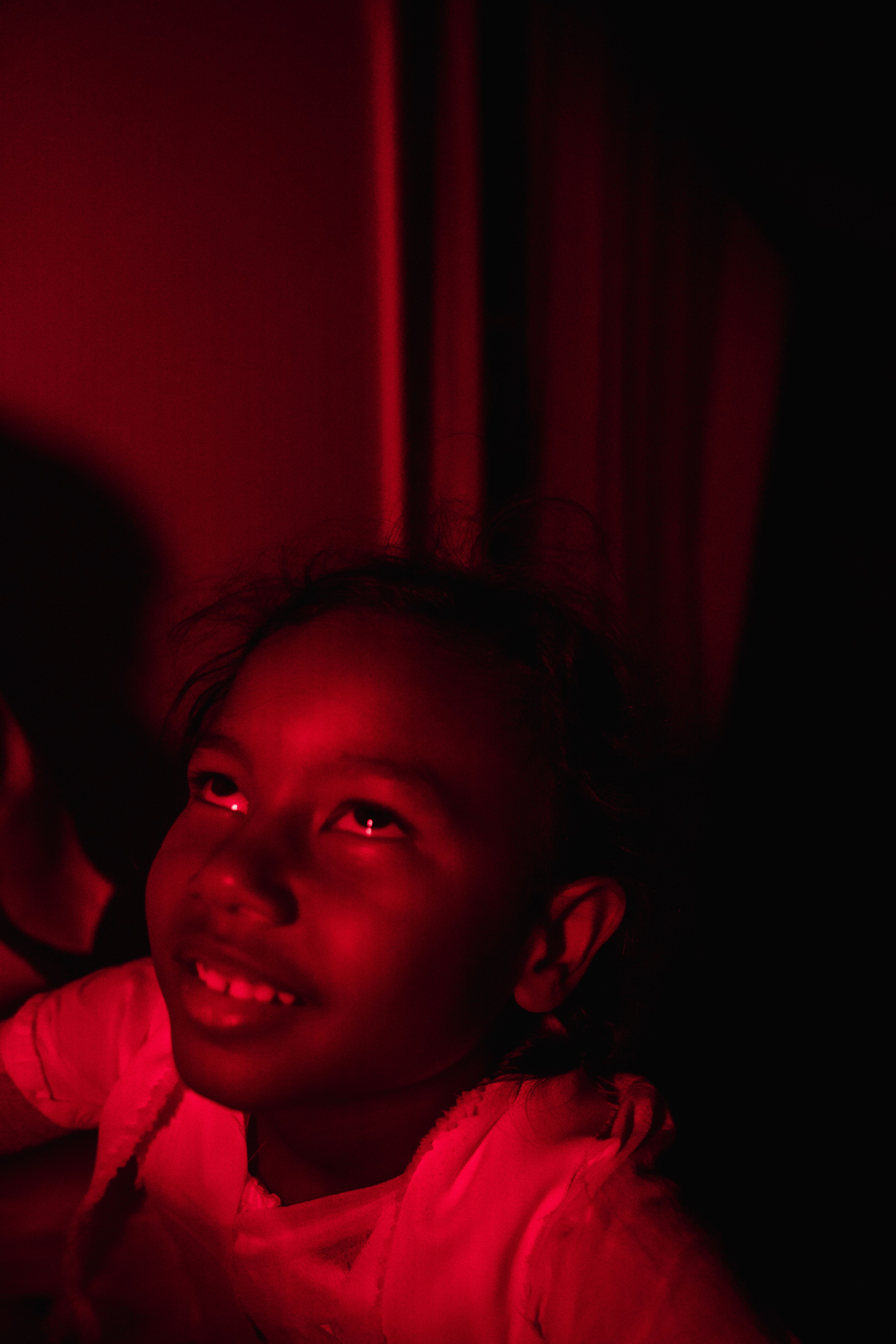 Blackskined girl in red-lighted room looking up · Free Stock Photo