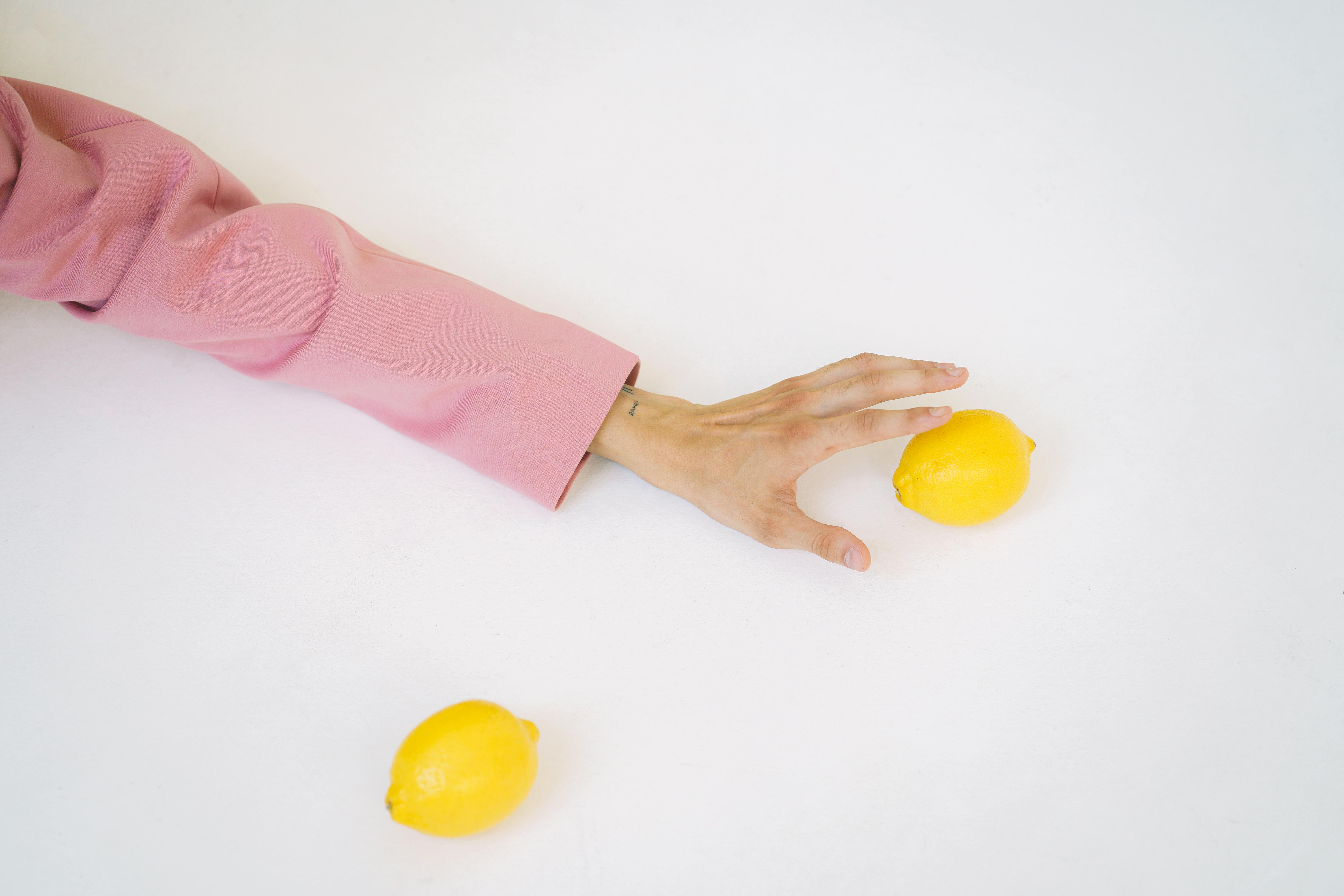 Arm reaching out towards lemon · Free Stock Photo