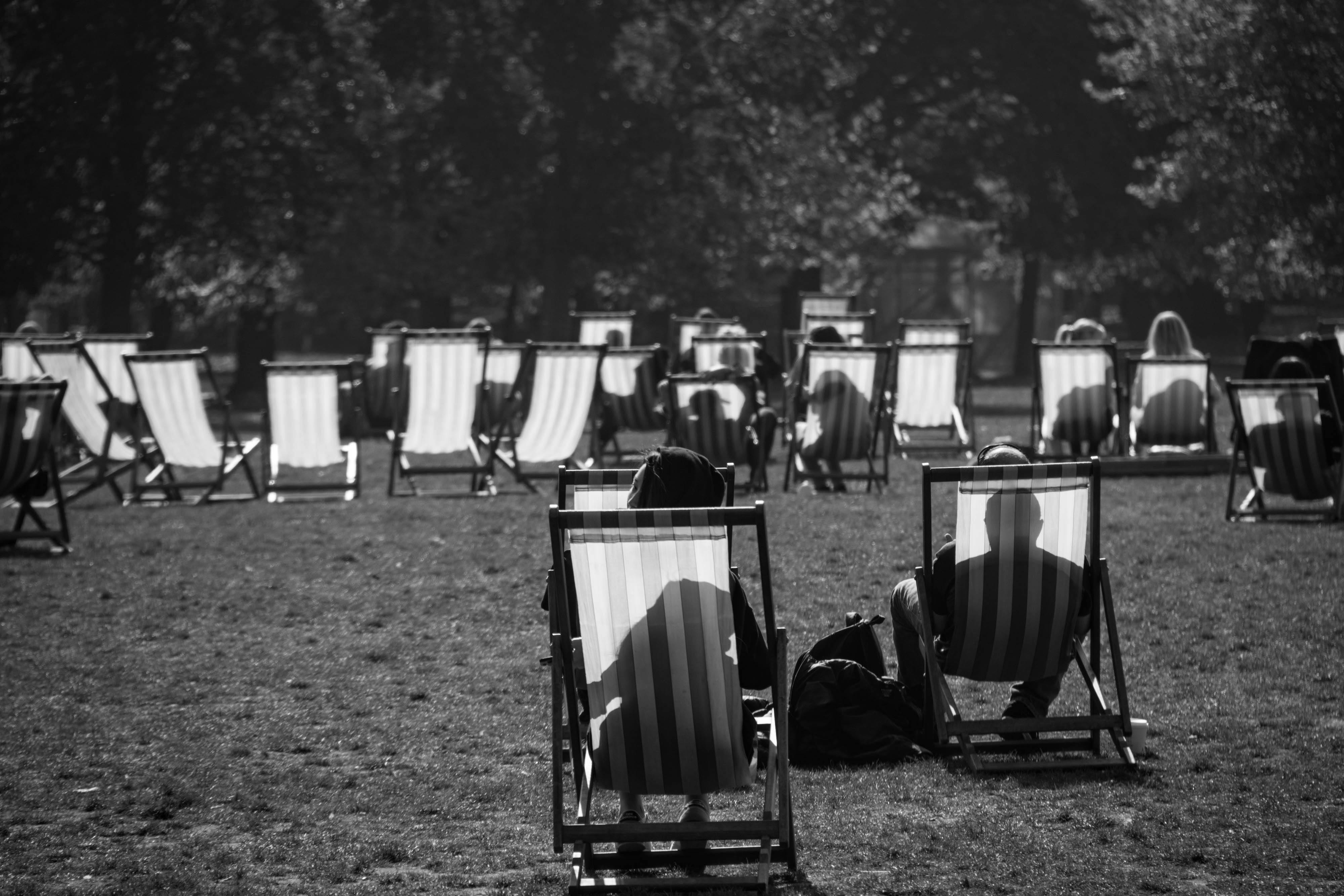 A Grayscale of People Sitting on Outdoor Folding Chairs at a Park ...