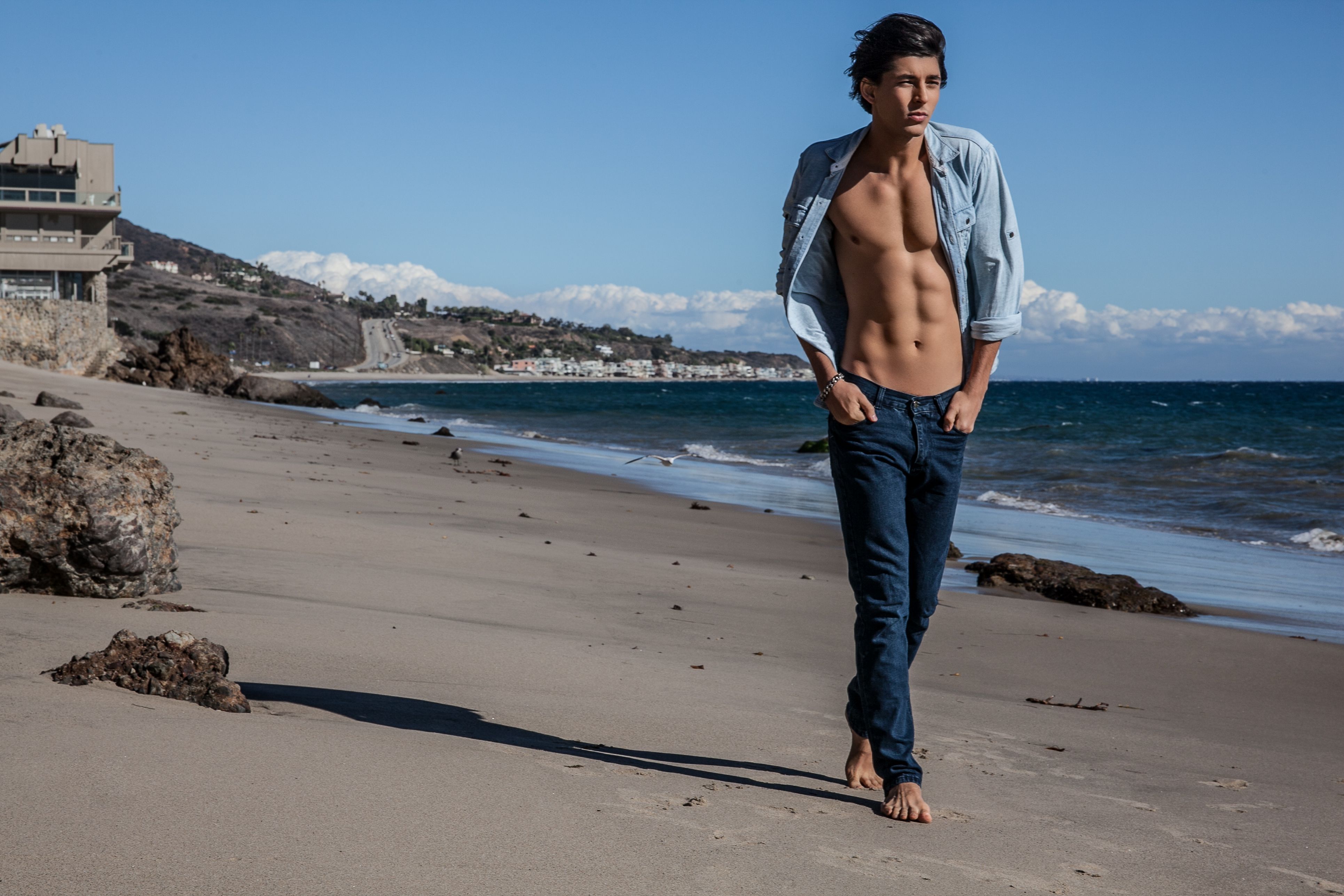 Man in Unzipped Shirt Walking on Beach · Free Stock Photo
