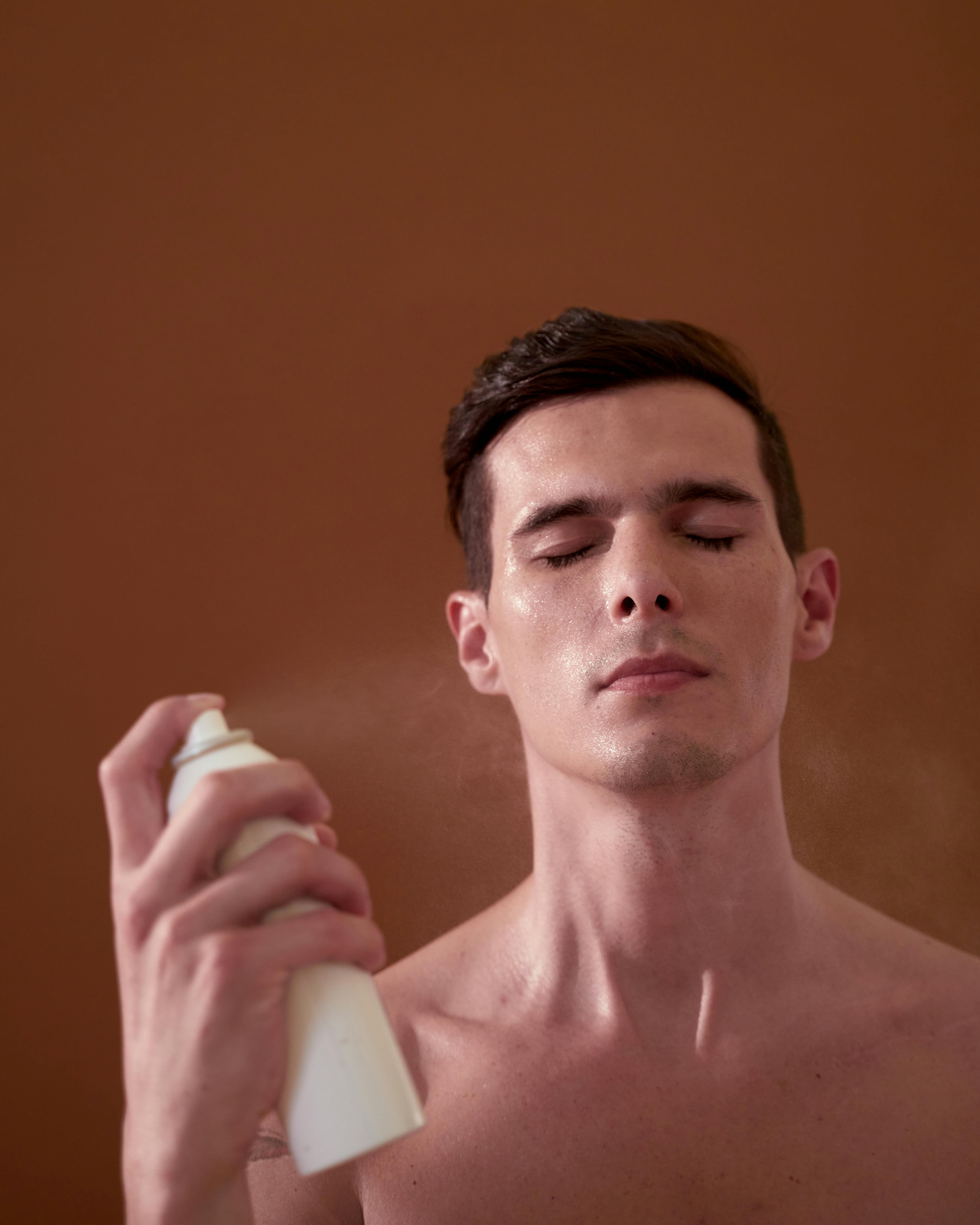 A Shirtless Man Spraying a Skin Care Product on His Face · Free Stock Photo