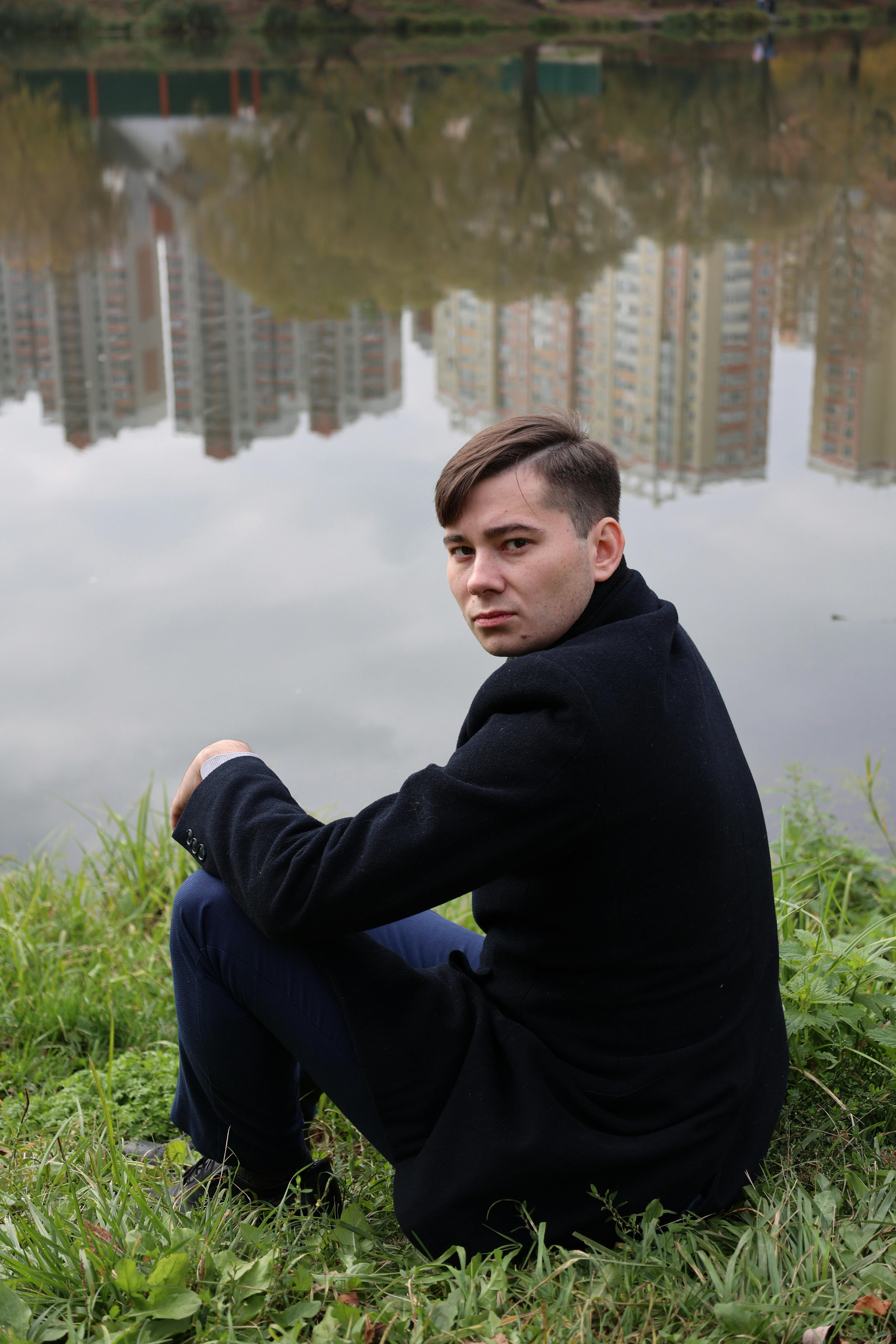 Man Sitting on Grass Looking Over His Shoulder · Free Stock Photo