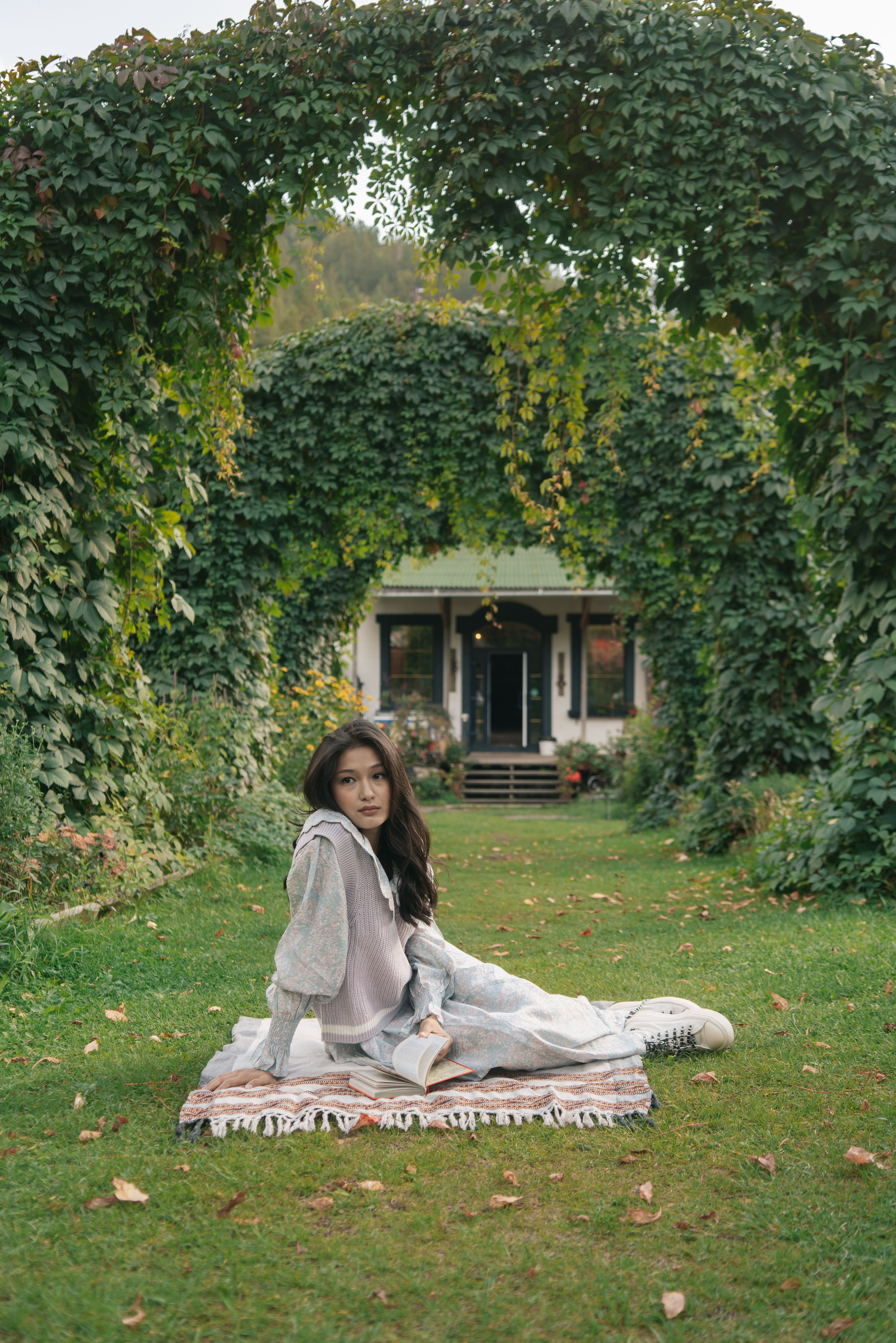 Woman Sitting on Rug Under Ivy Arch · Free Stock Photo