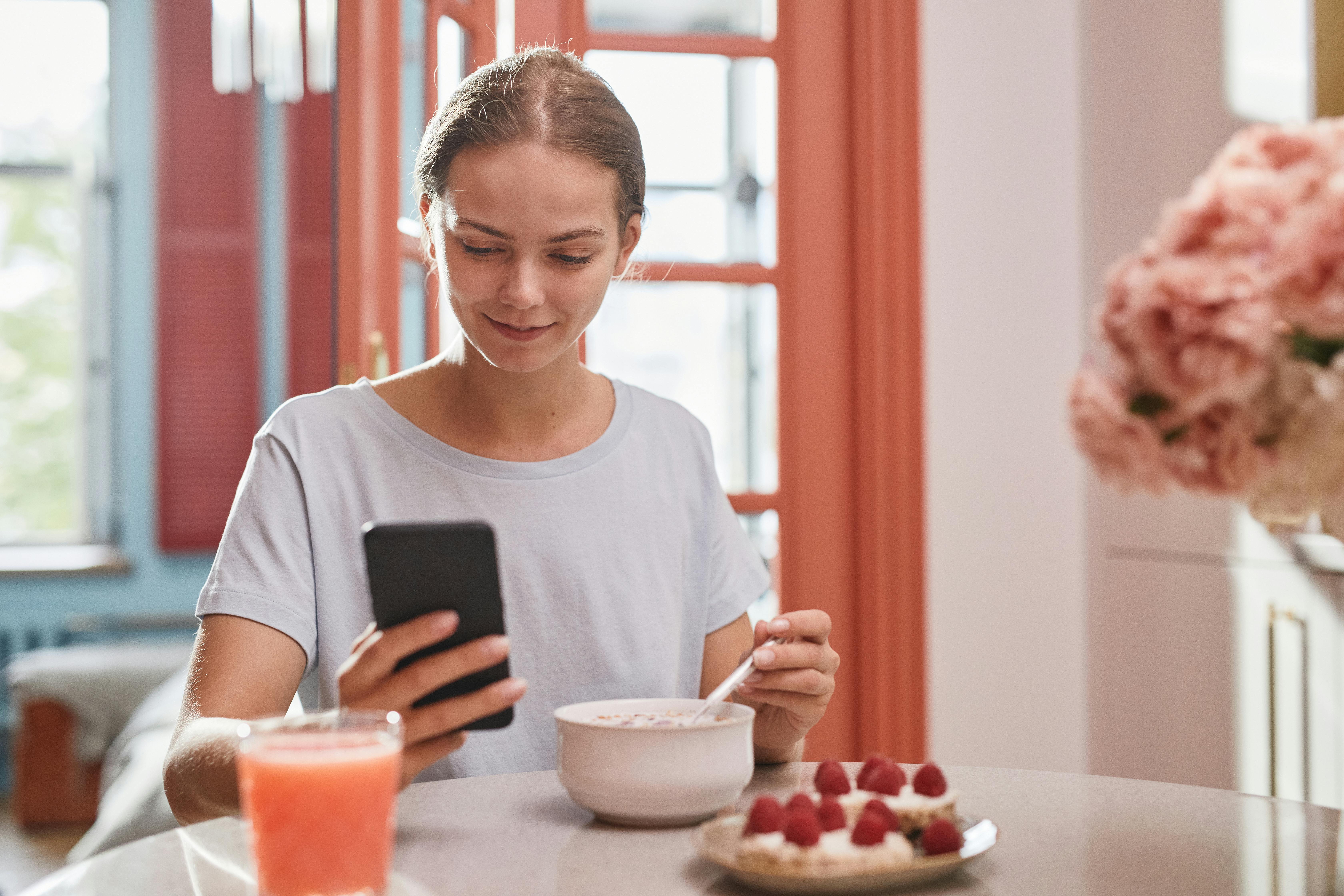Woman Browsing Her Smartphone While Eating · Free Stock Photo