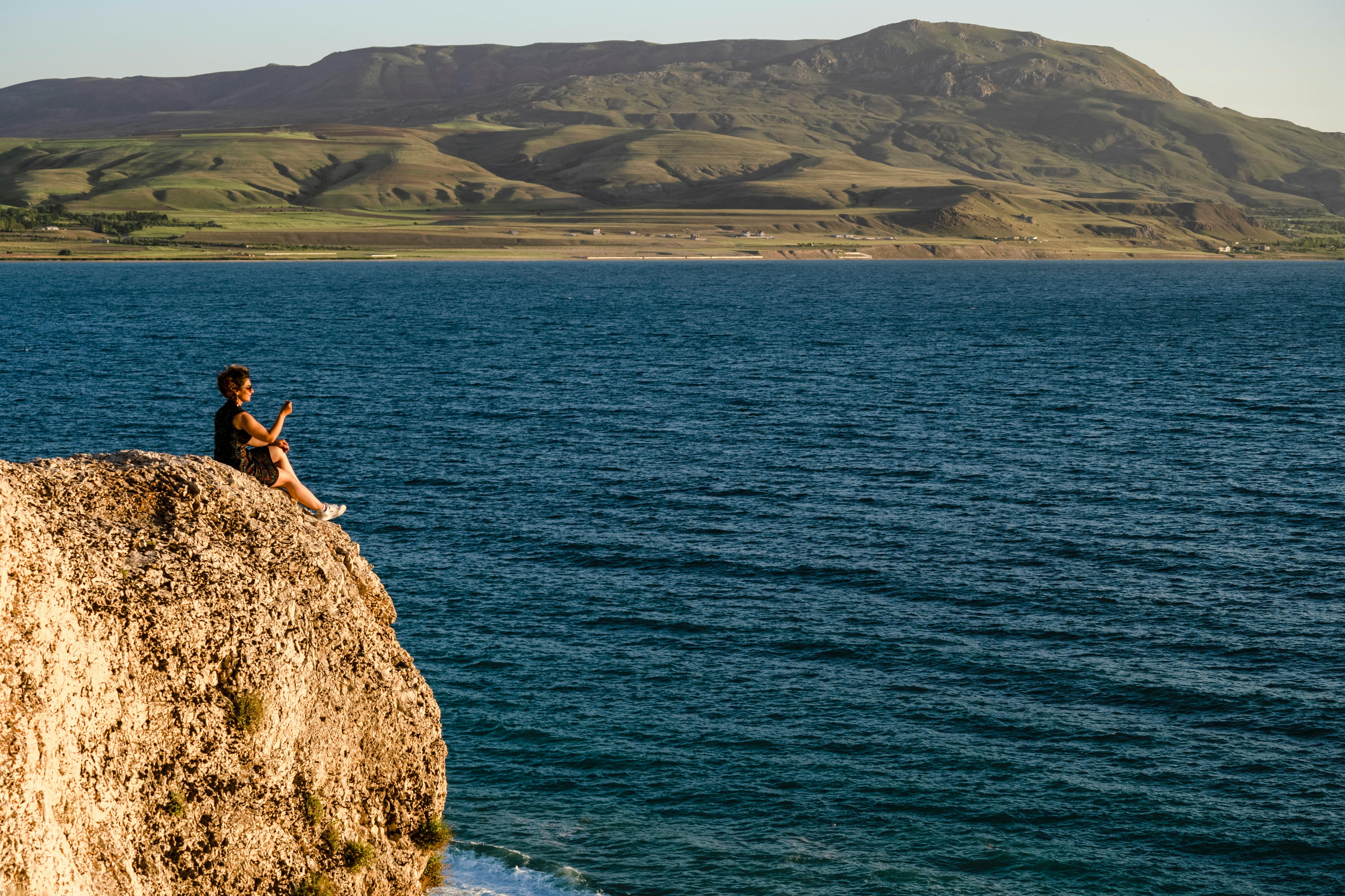 A Person Sitting on a Rock by a Lake · Free Stock Photo