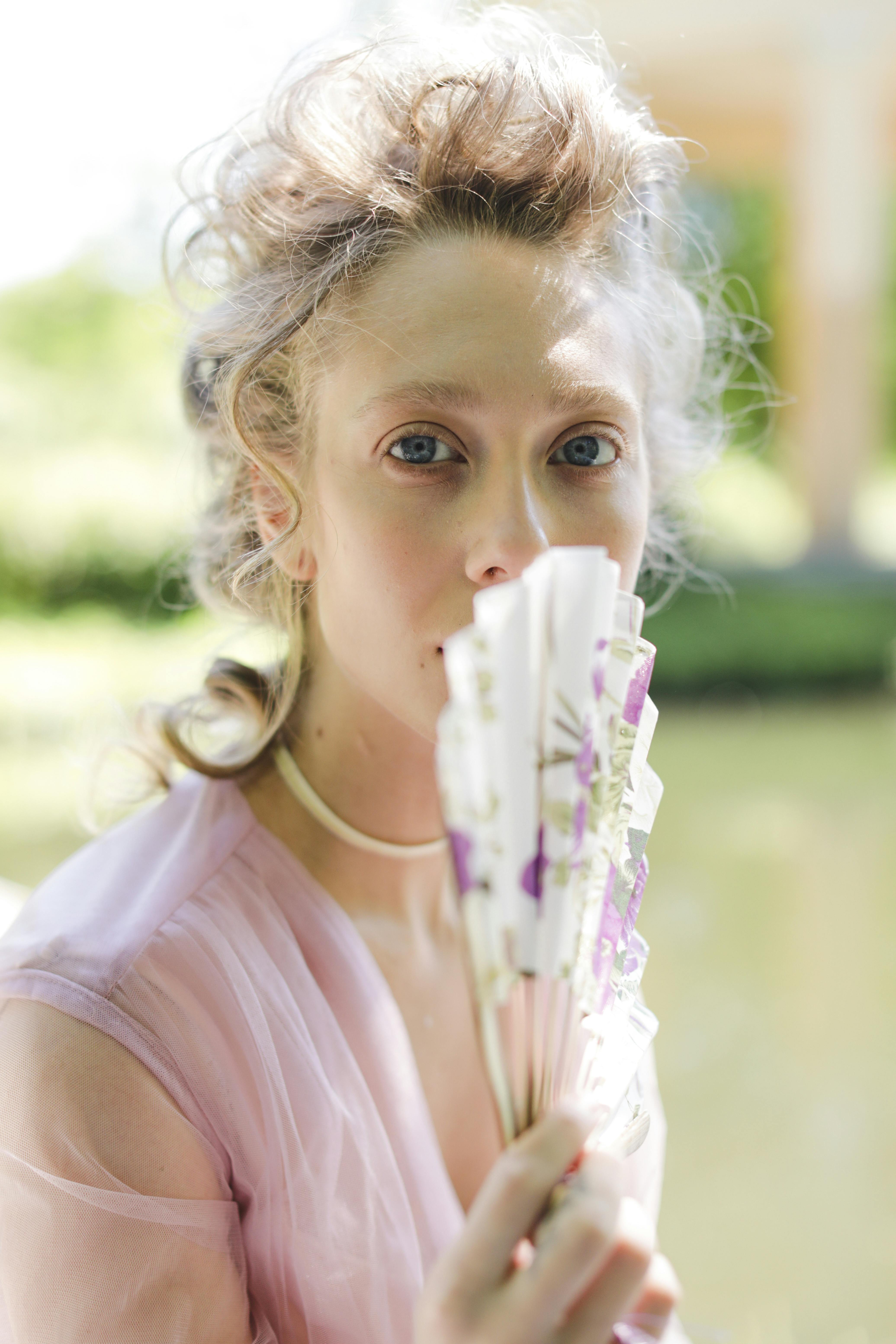 A Close-Up Shot of a Woman Holding a Hand Fan · Free Stock Photo