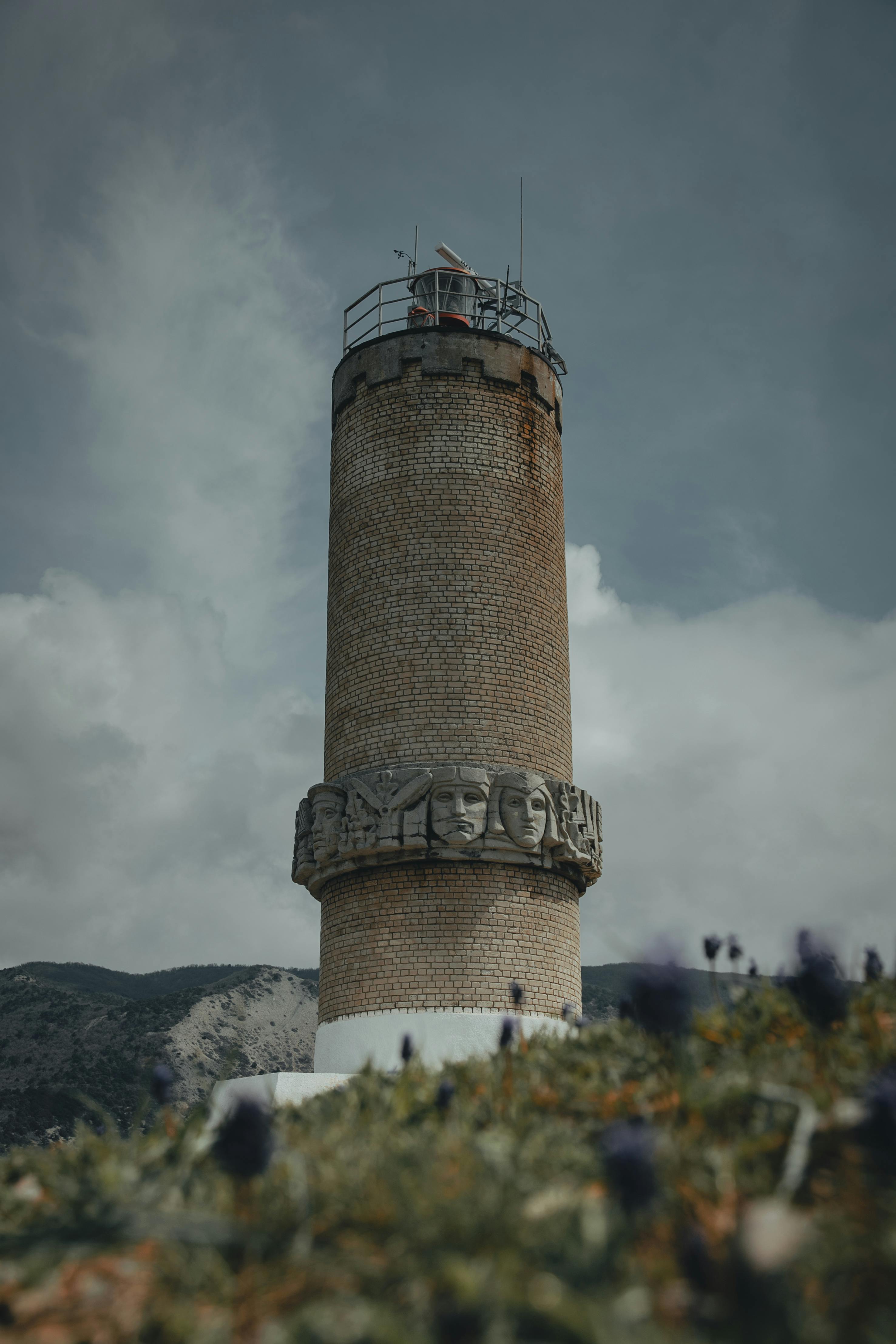 Tower in hilly area with face sculptures around it · Free Stock Photo