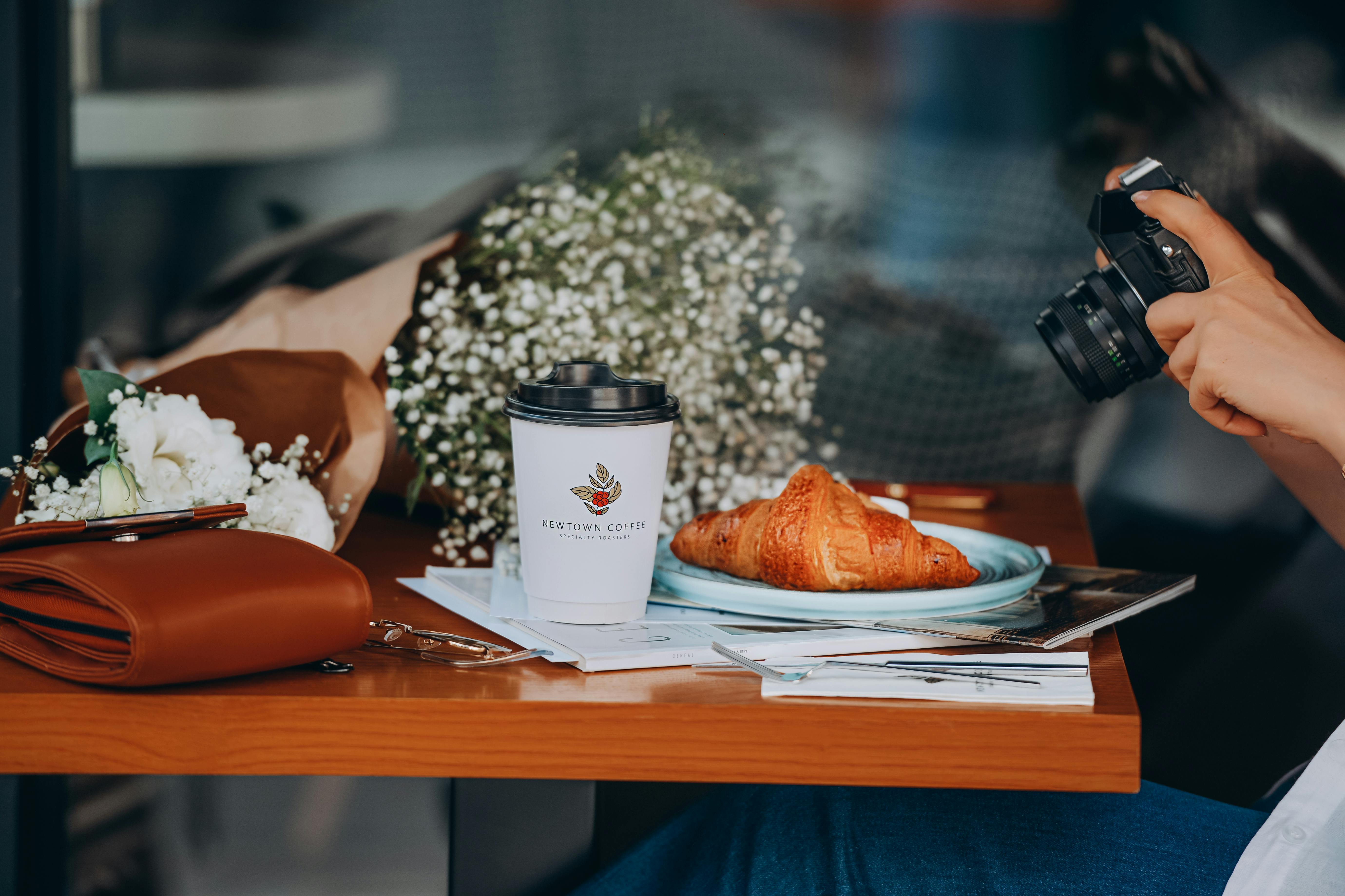 Human hand taking photo of croissant and cup of coffee · Free Stock Photo