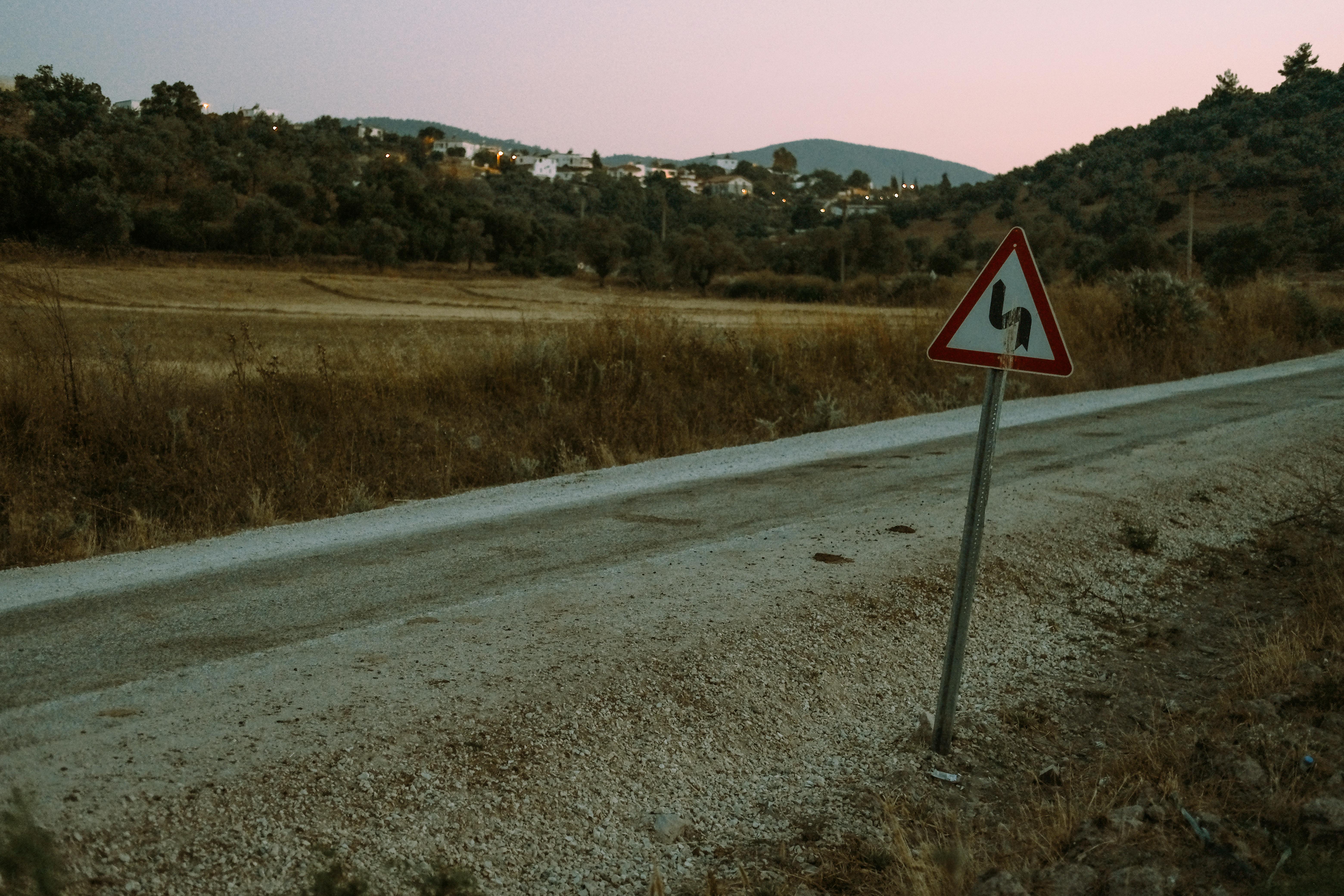 A Red and White Double Curve Road Sign on a Steel Pole · Free Stock Photo