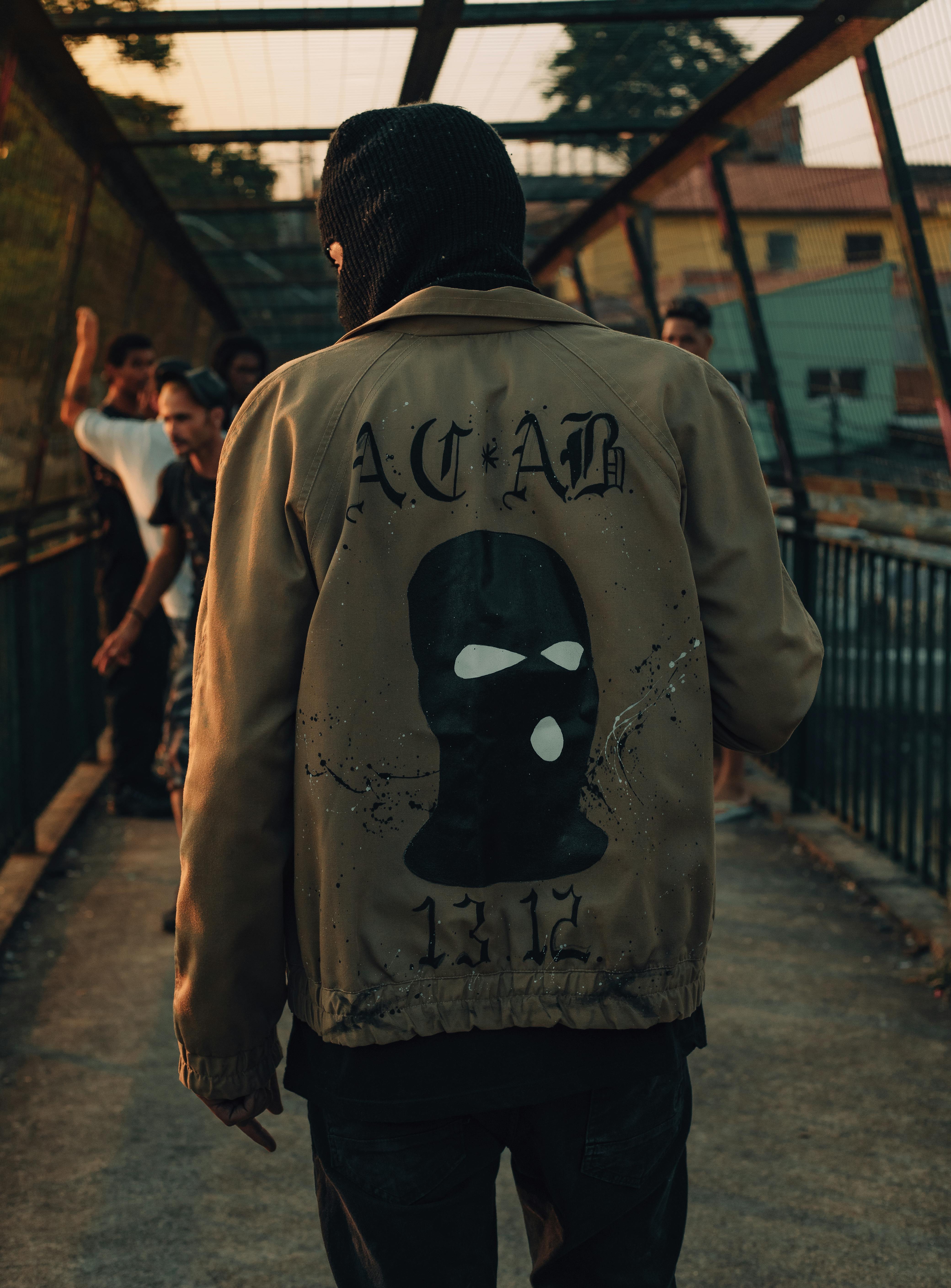 Man in Black Balaklava and Jacket Walking on Bridge · Free Stock Photo