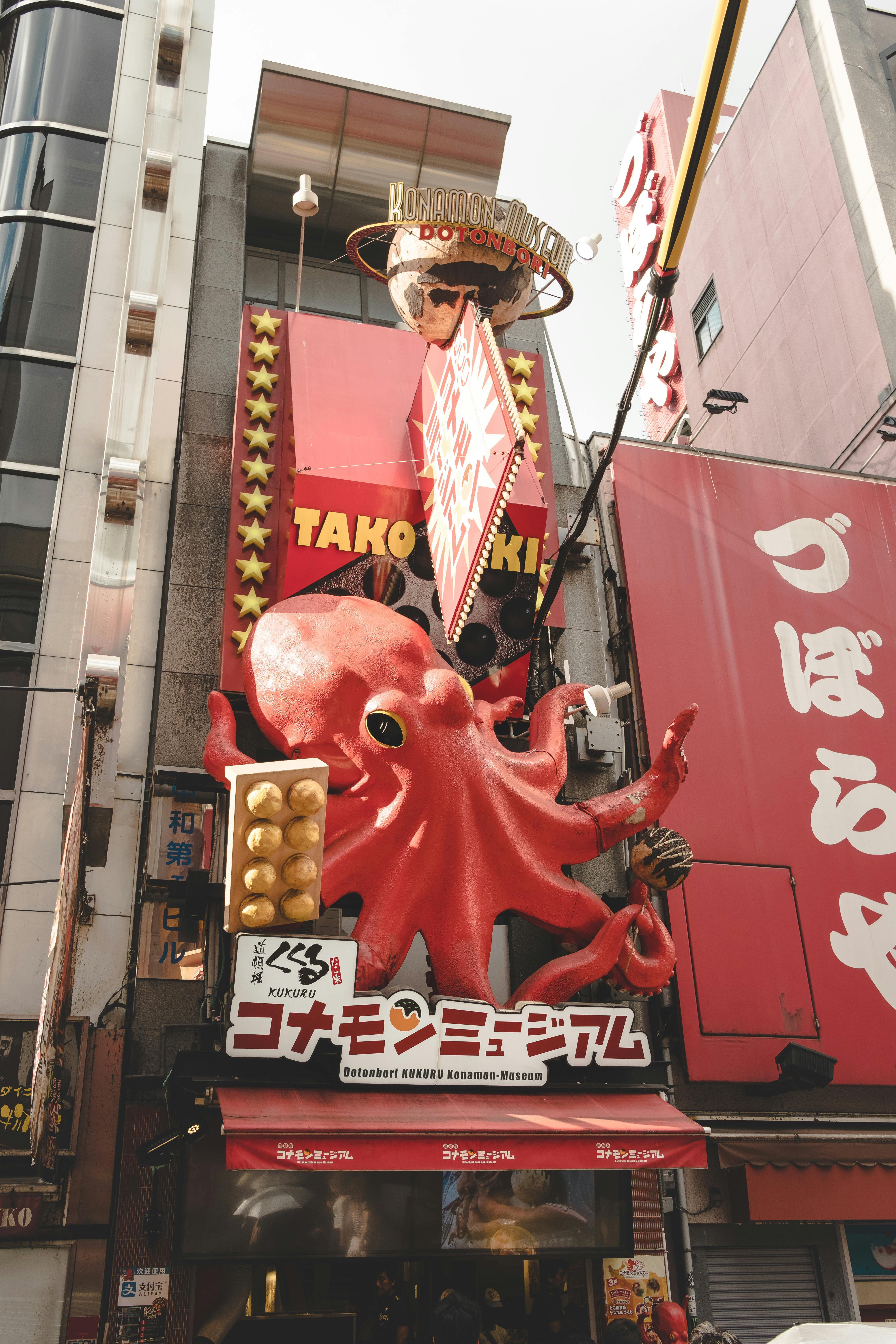 A Red Squid Sculpture Under a Store Signage · Free Stock Photo