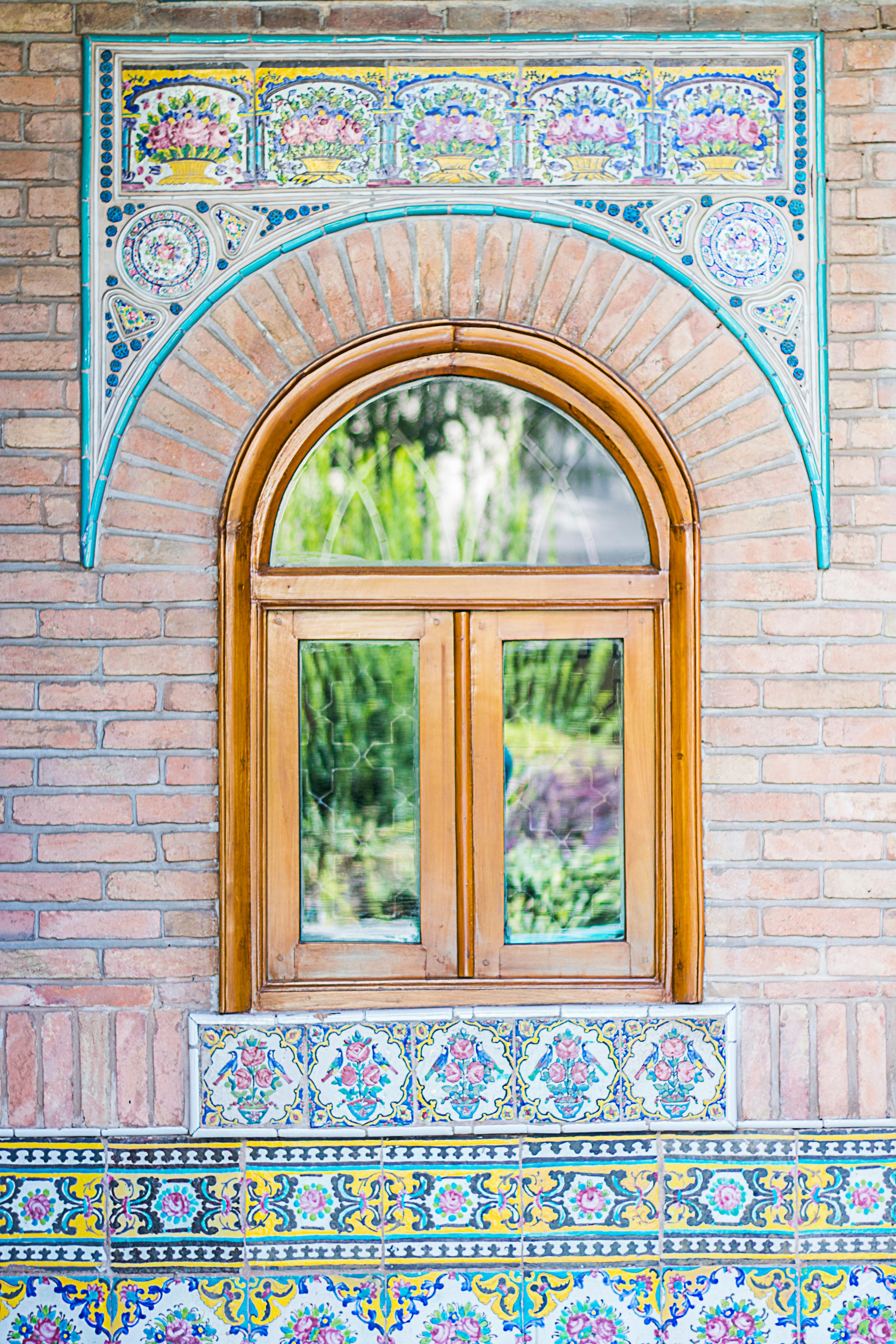 Wall with wooden arch window and ornamental tiles · Free Stock Photo