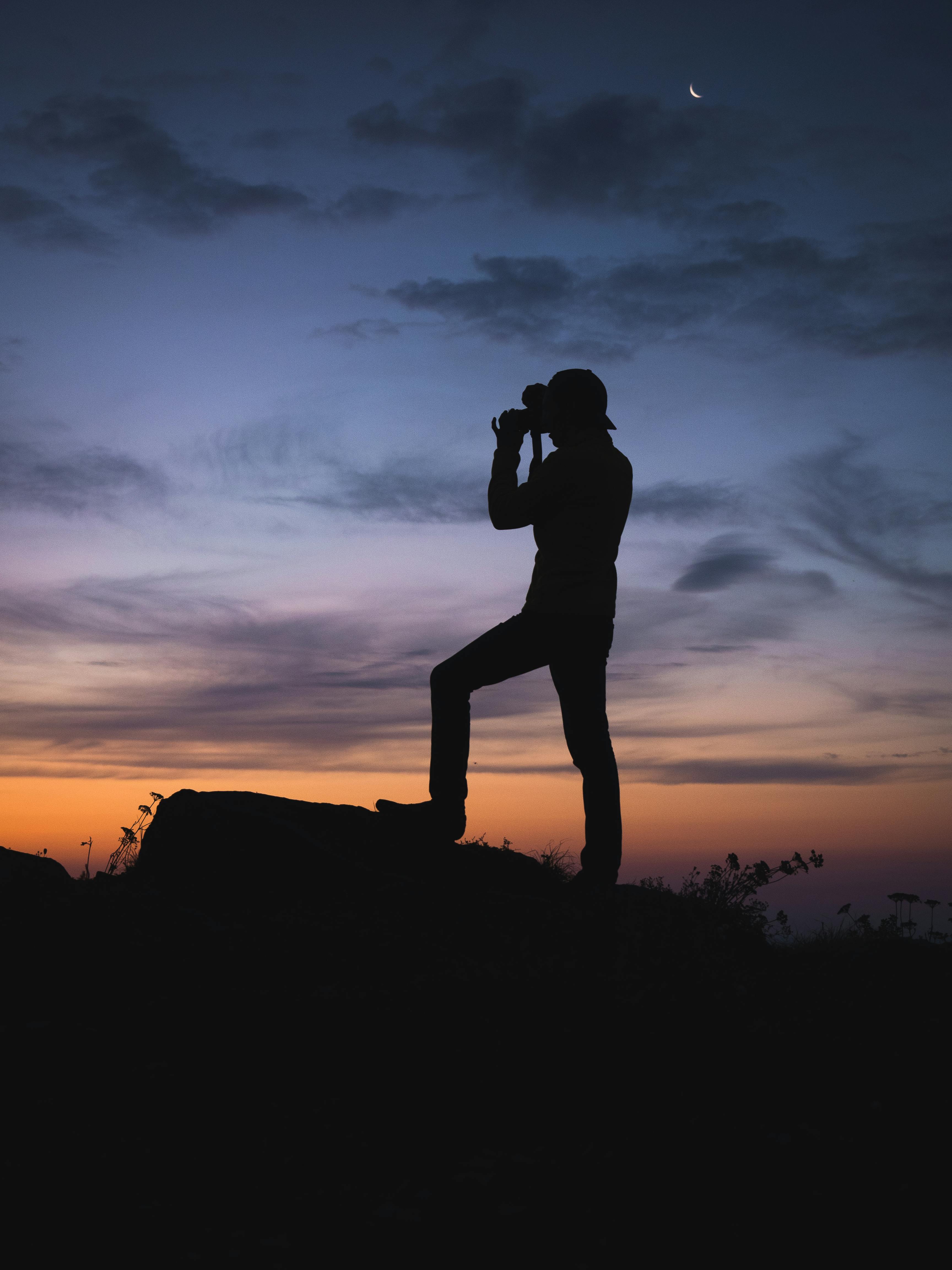Man Using Binoculars in Between Stack of Books · Free Stock Photo