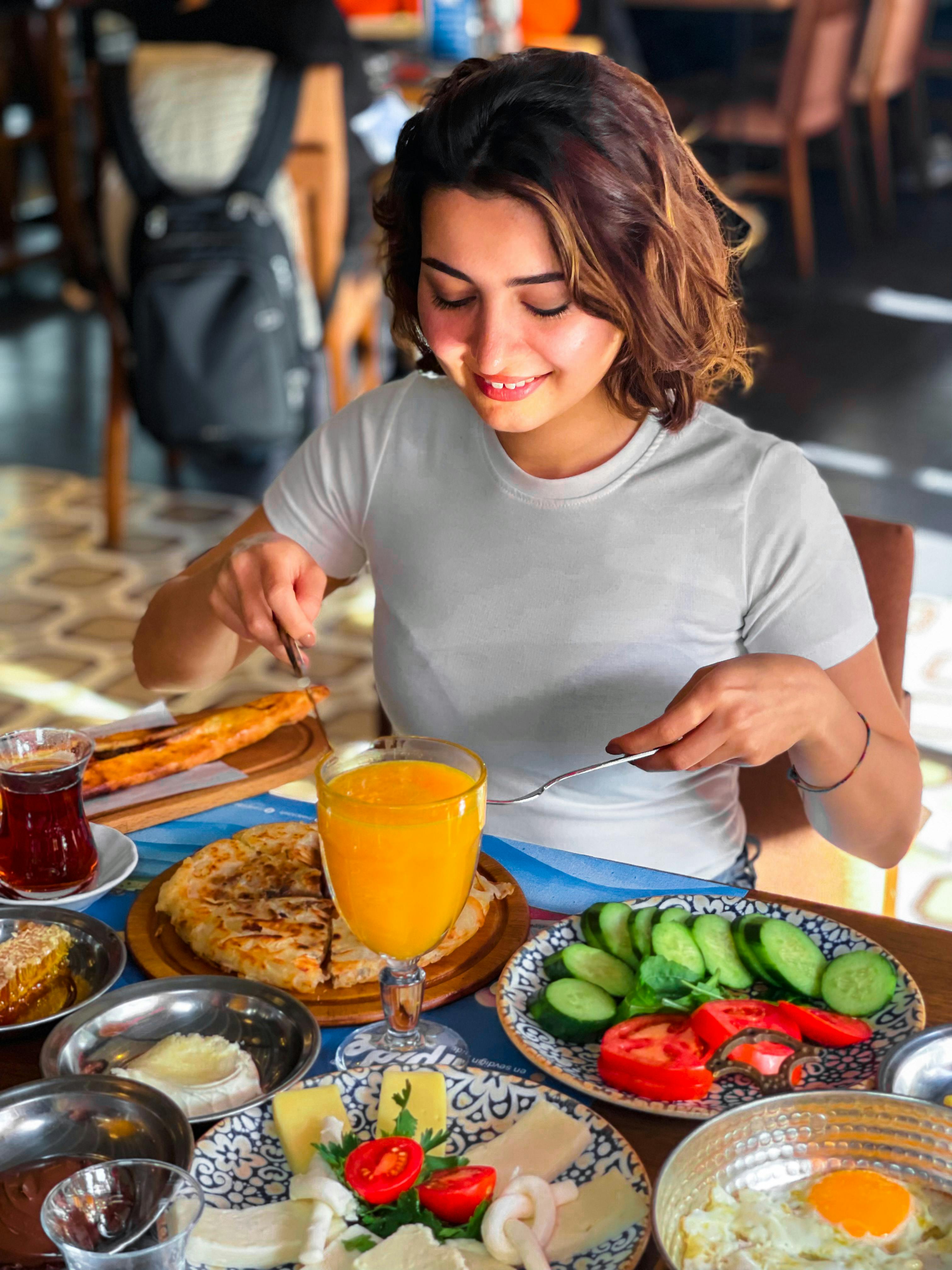 Smiling Woman Eating at Table in Restaurant · Free Stock Photo