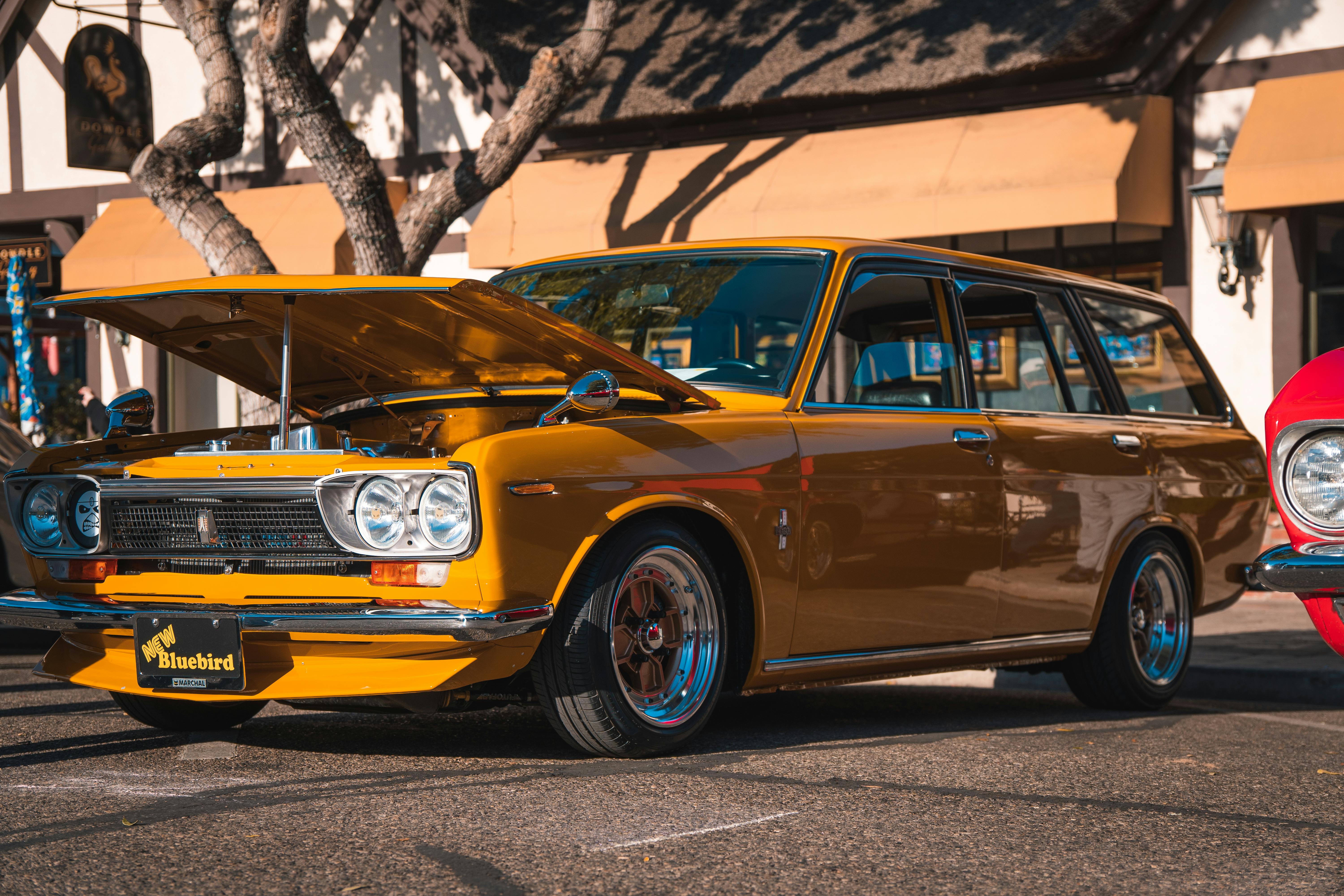 Shiny Yellow Station Wagon Parked Beside a Tree · Free Stock Photo