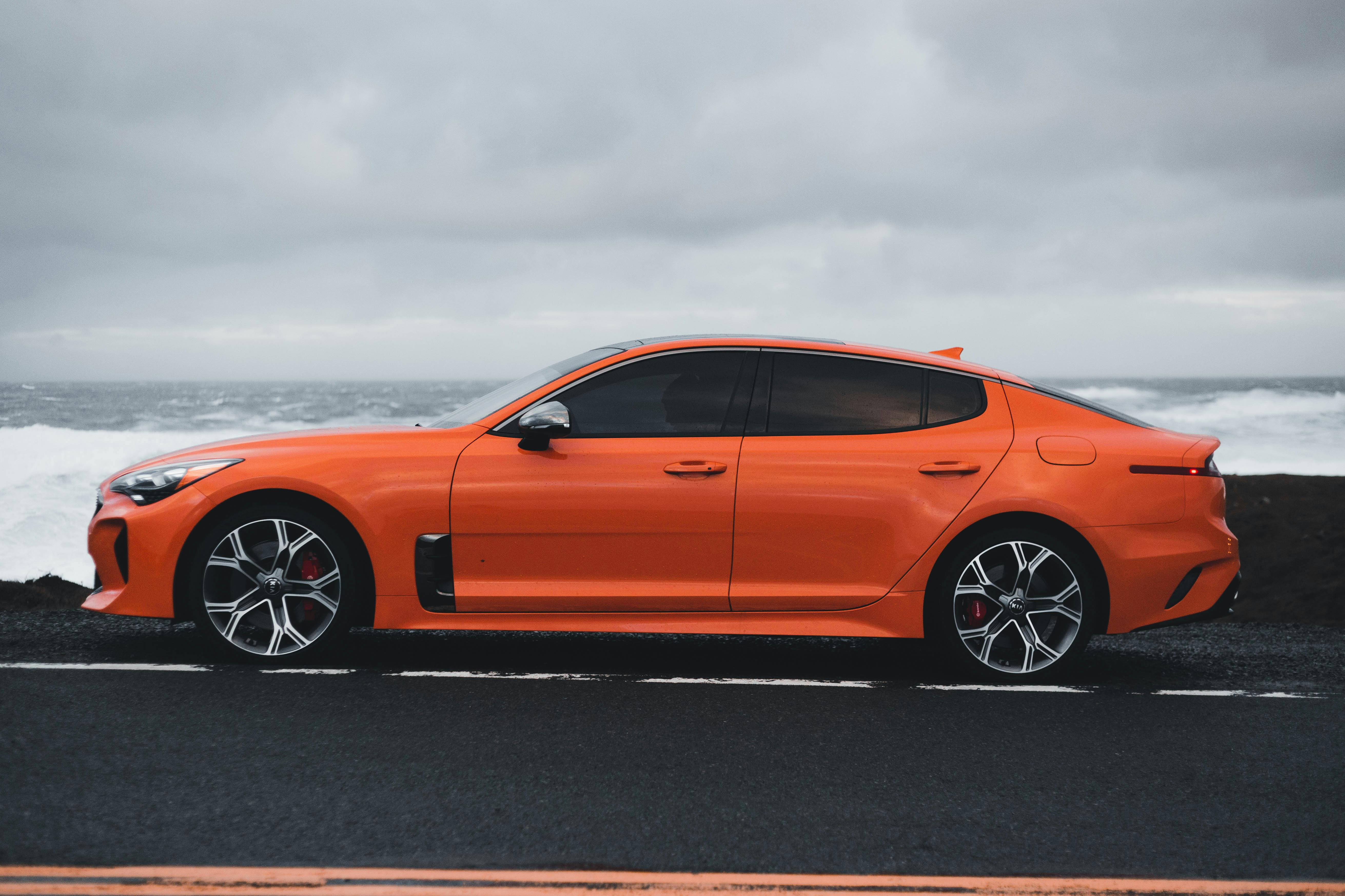 Orange Car Parked on the Roadside Near Body of Water · Free Stock Photo