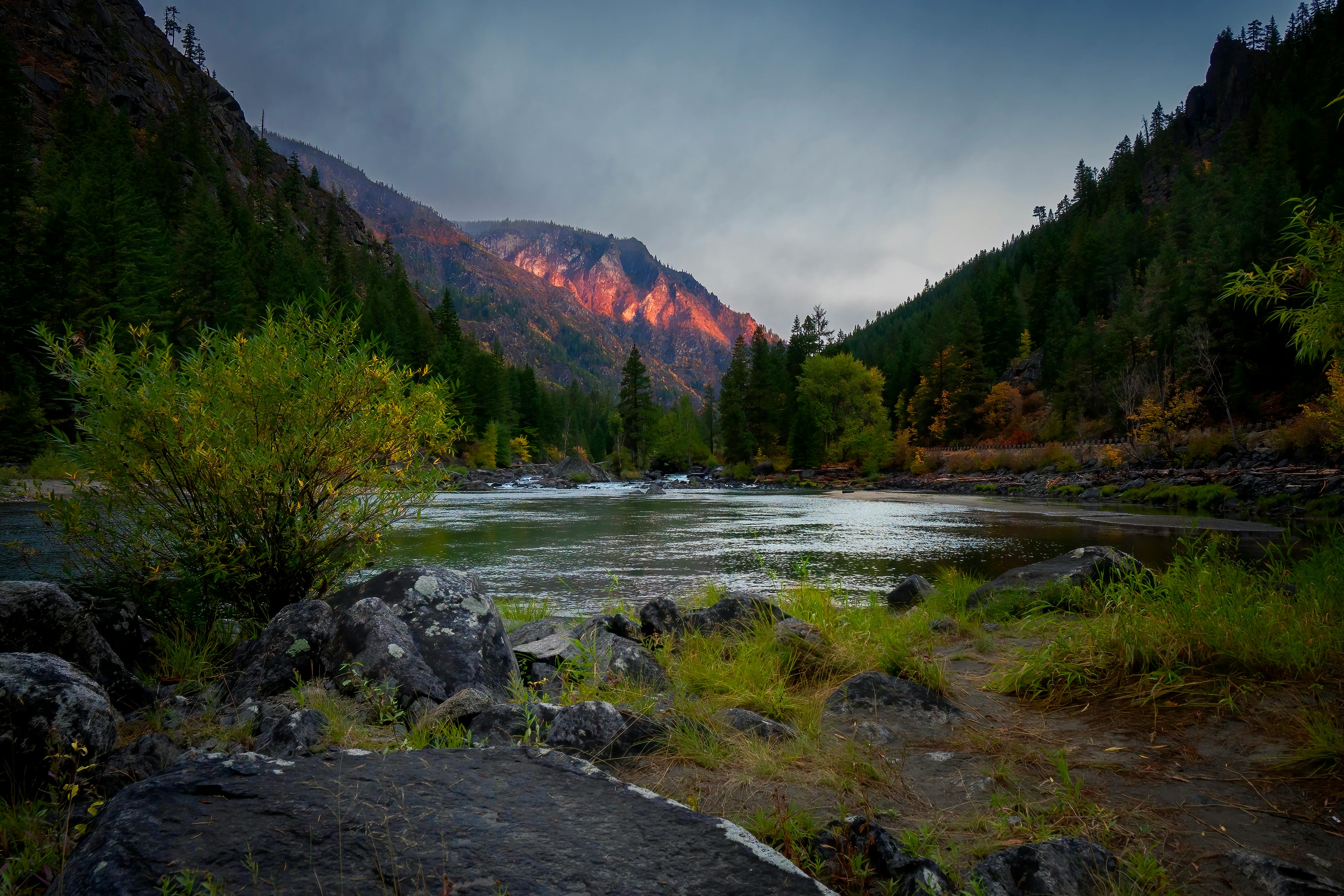 Two People Sitting on a Cliff Overlooking the Scenic View of a Placid ...