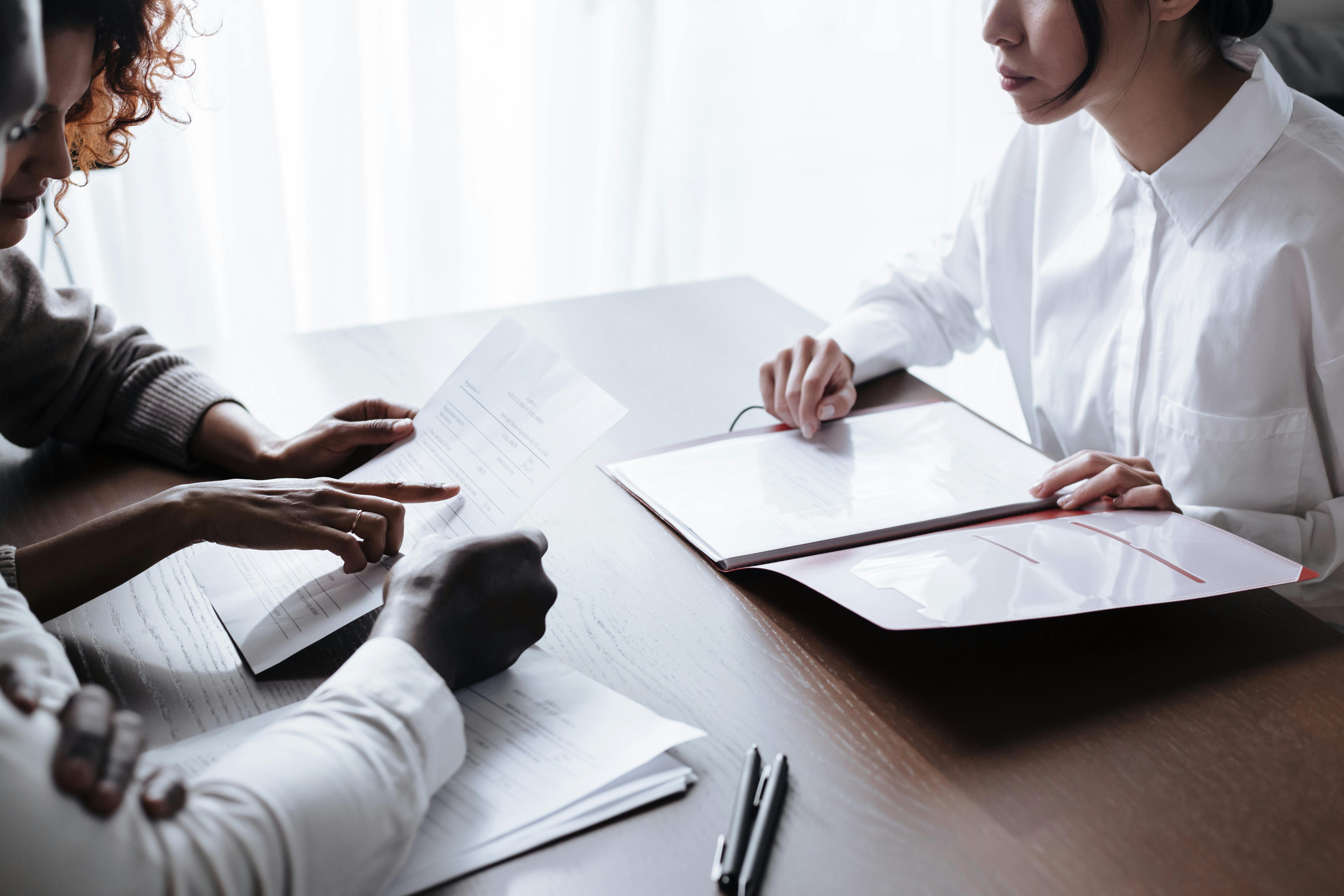 Couple Sitting at Table with Documents Laying on It · Free Stock Photo