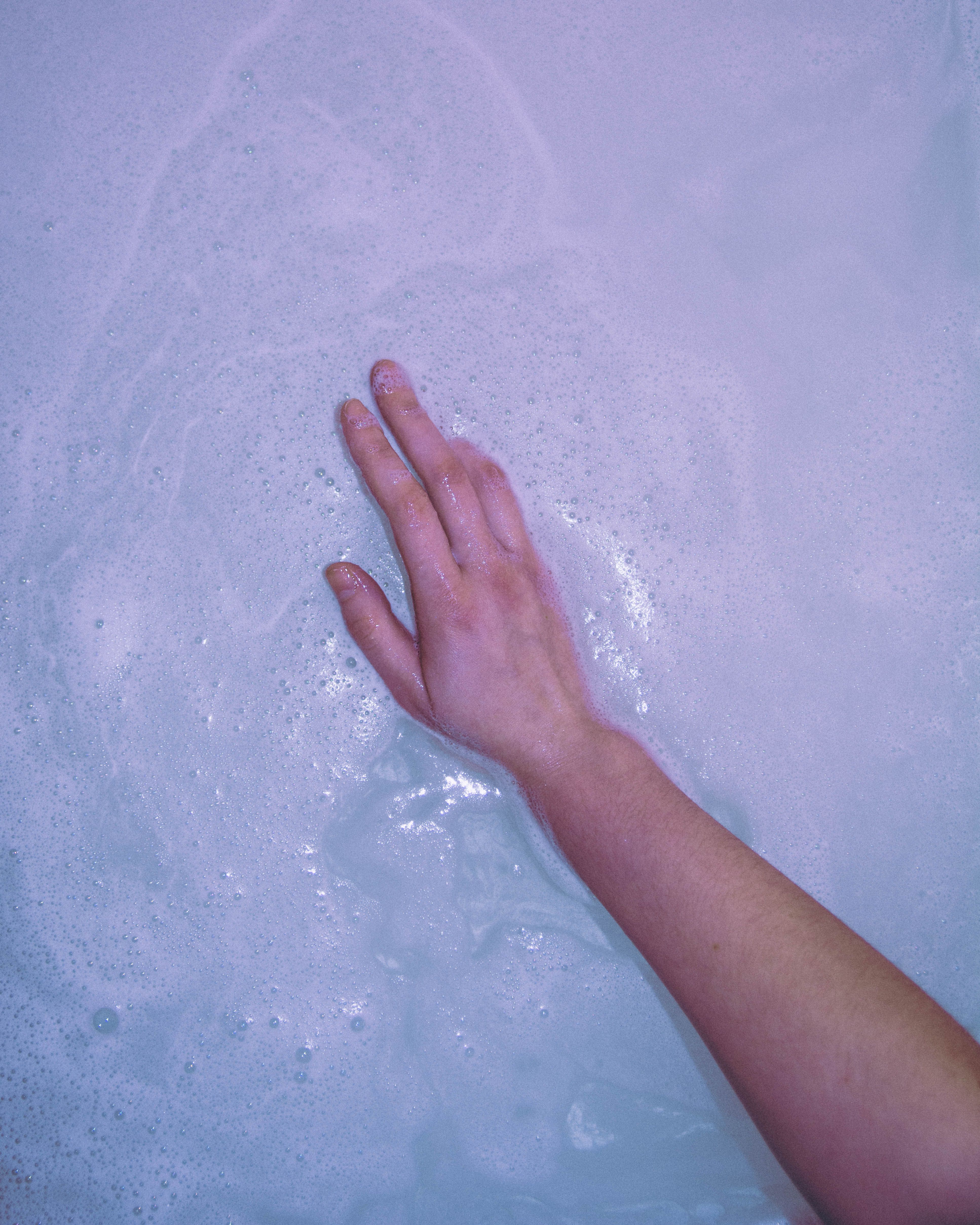 A Person Touching the Soap Foam on Water · Free Stock Photo