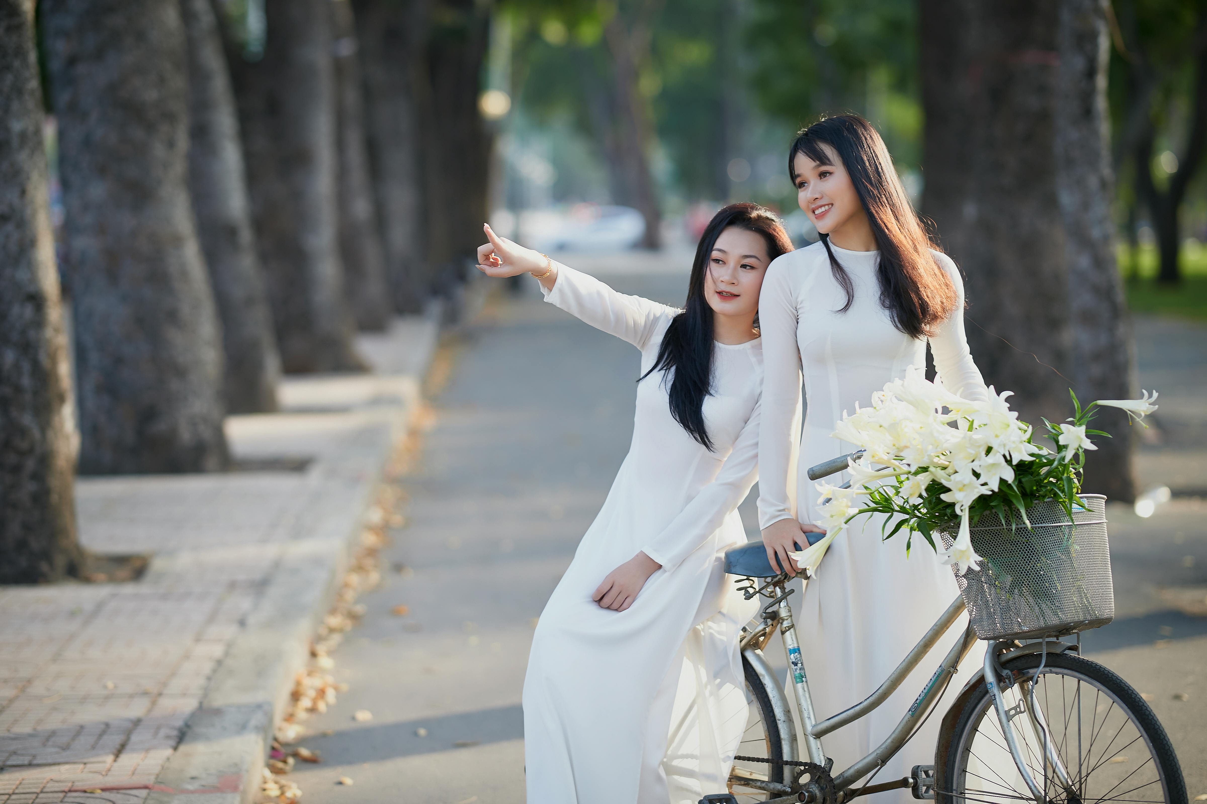 Women Wearing White Dresses Holding a Bicycle · Free Stock Photo