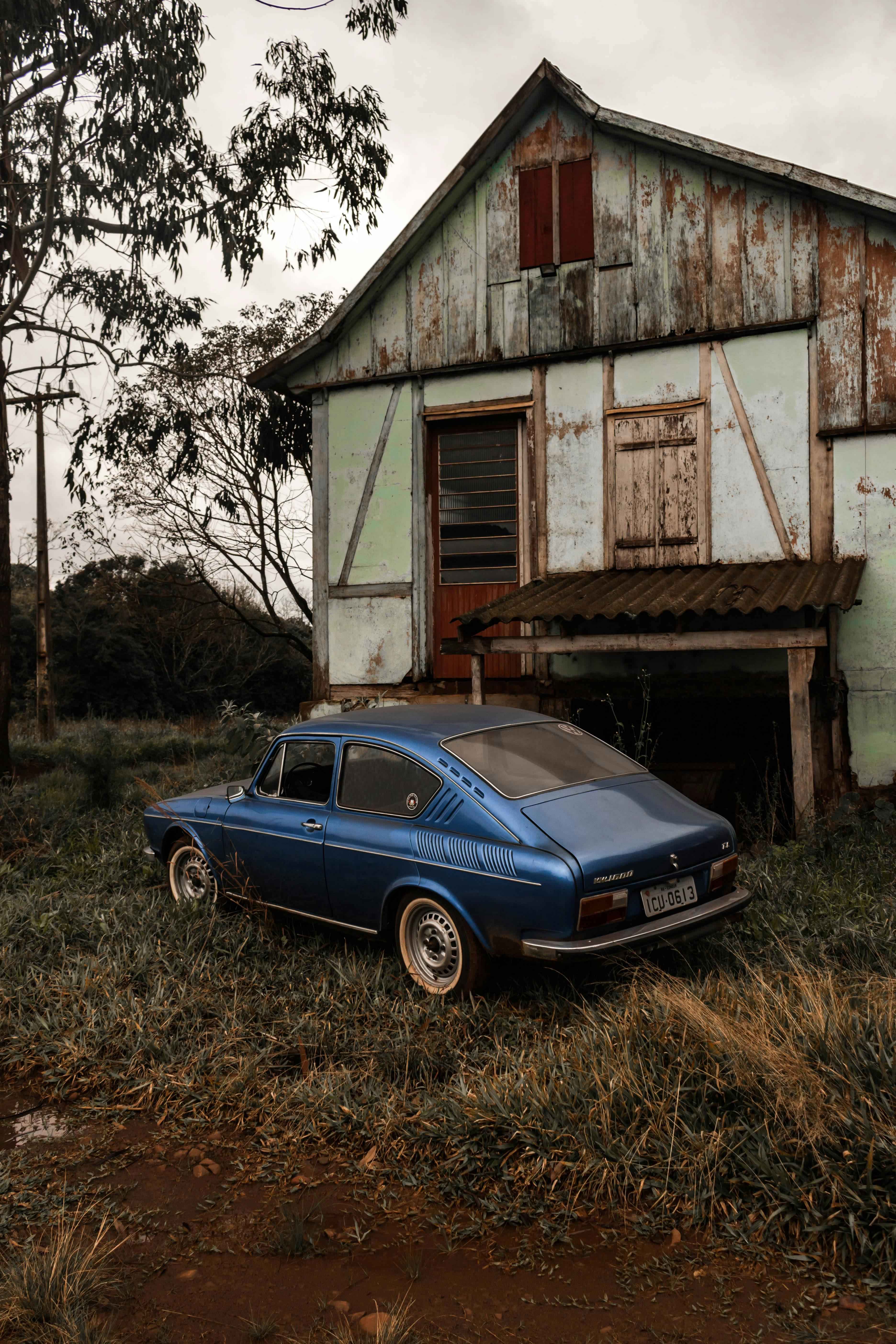 An Old Blue Car Parked Outside an Old House · Free Stock Photo