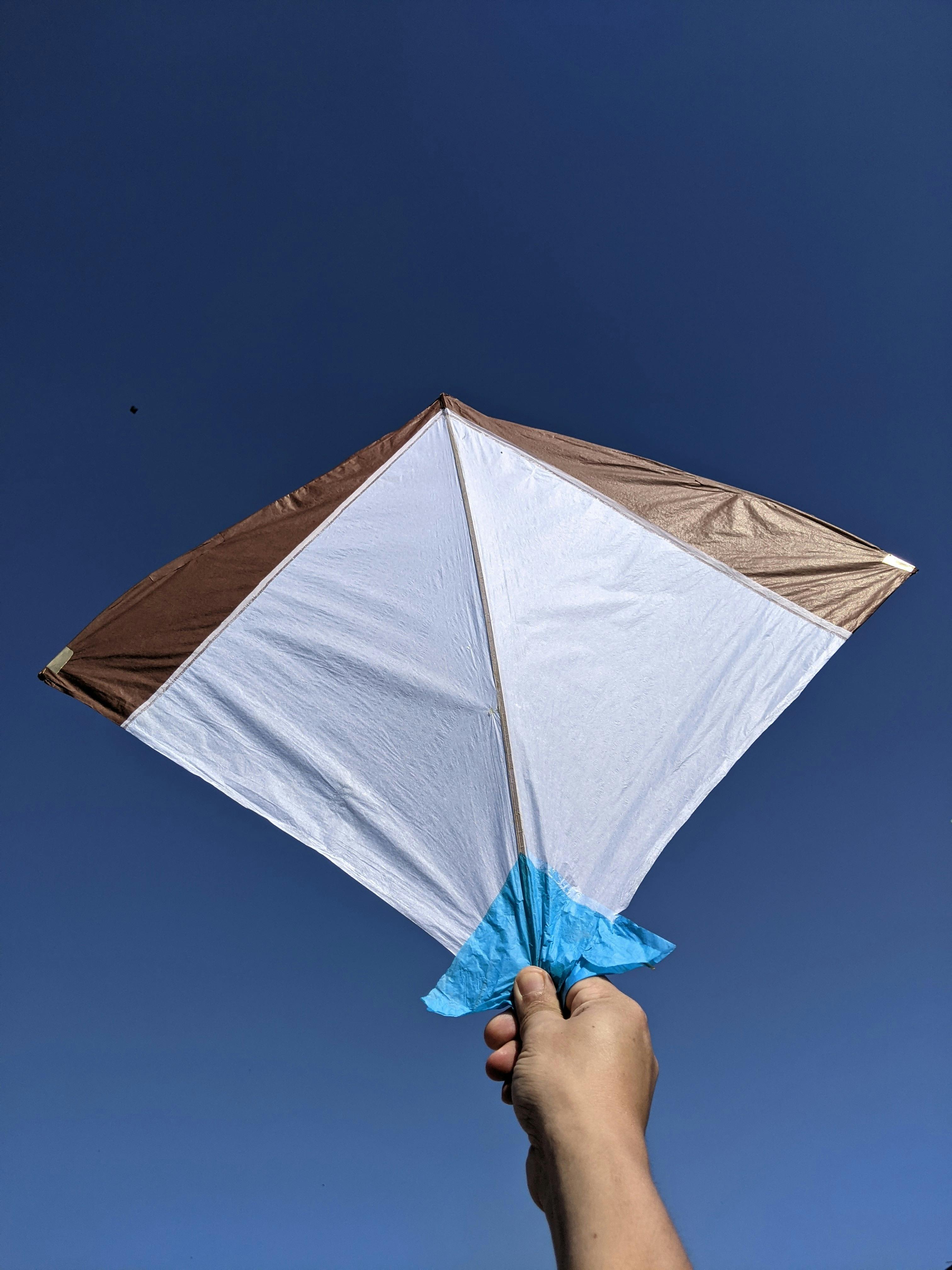 A Hand Holding a Kite Under the Blue Sky · Free Stock Photo