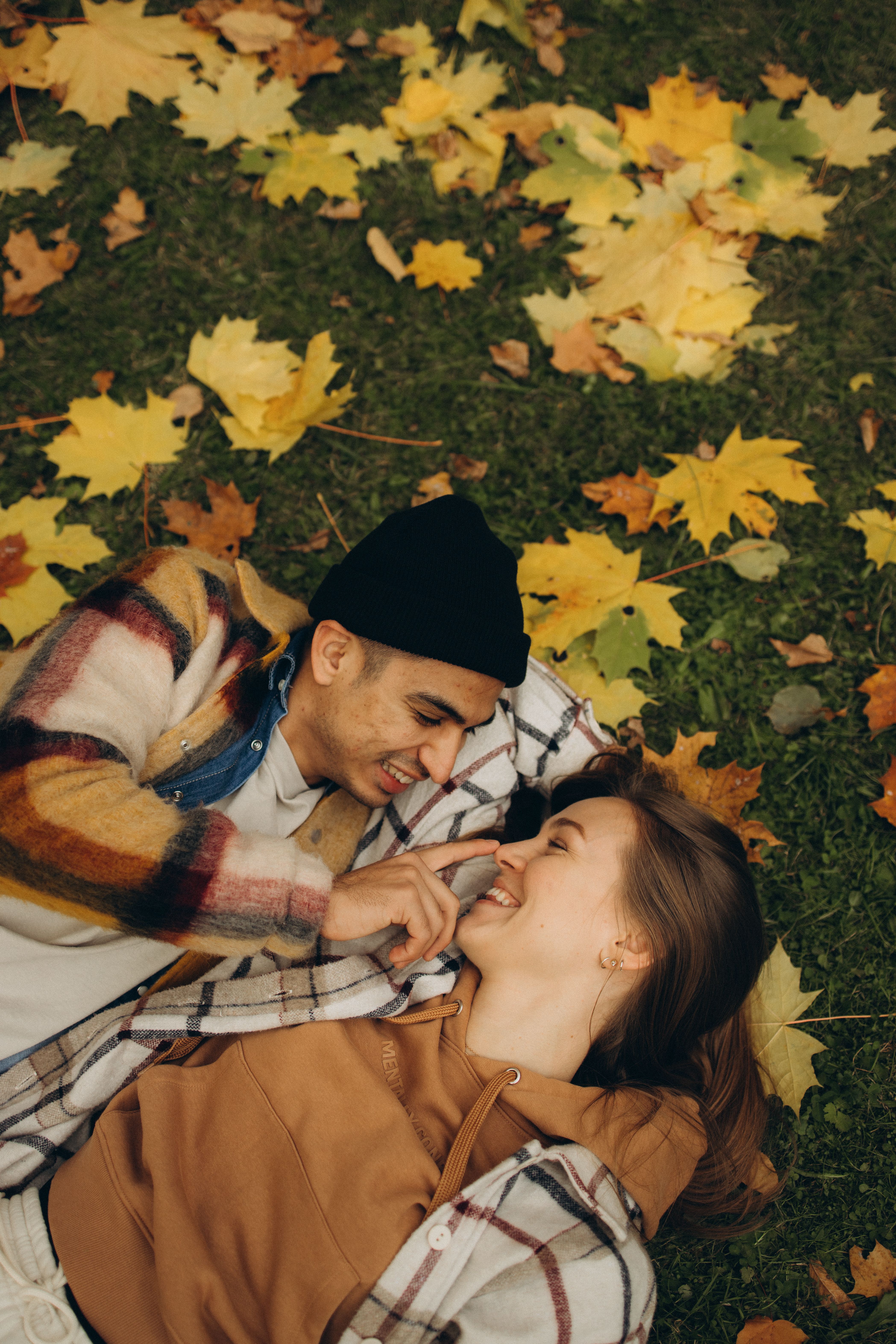 High-Angle Shot of a Romantic Couple Lying on the Grass with Autumn ...