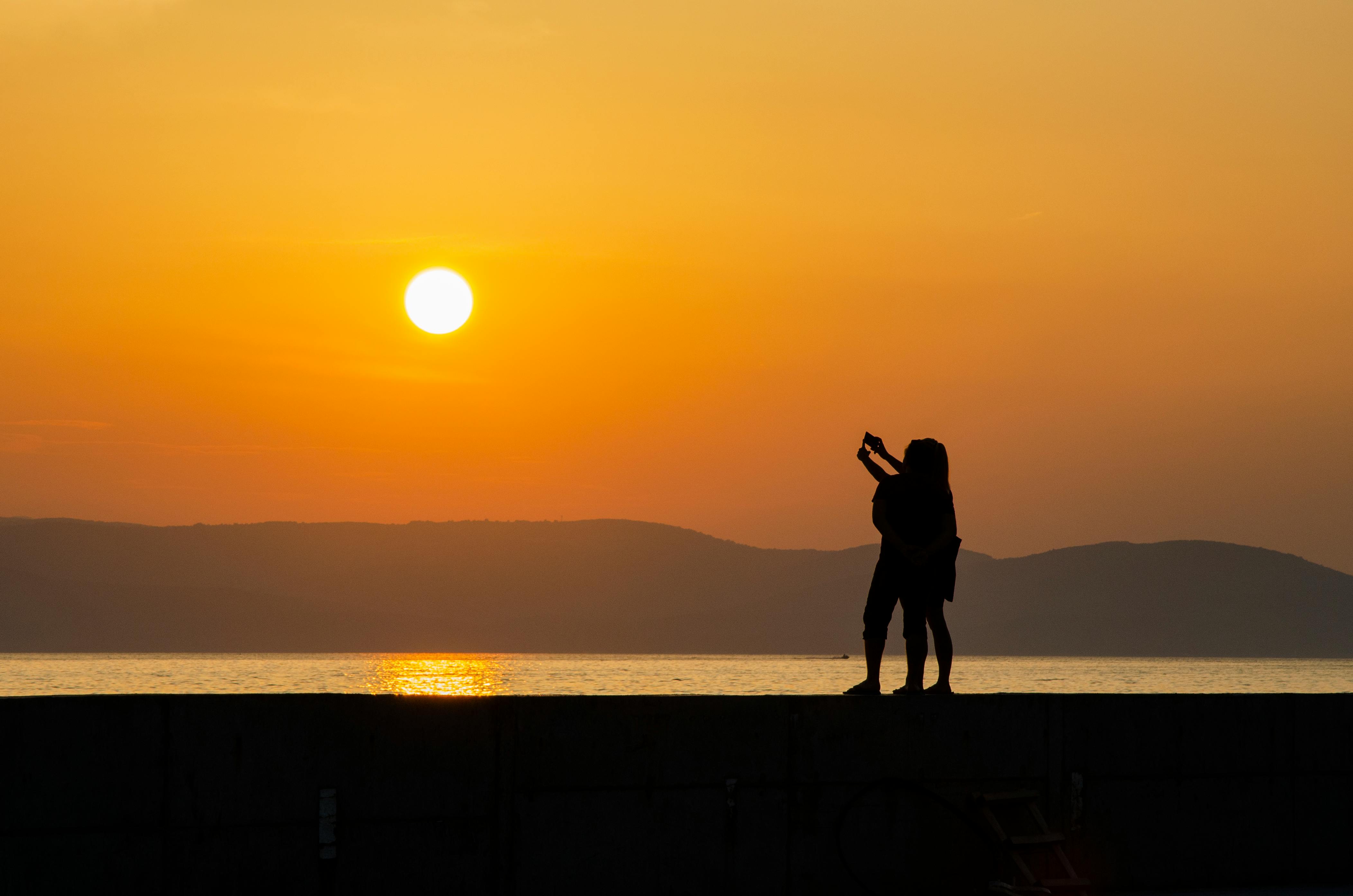 Silhouette of People Standing Near Body of Water During Sunset · Free ...