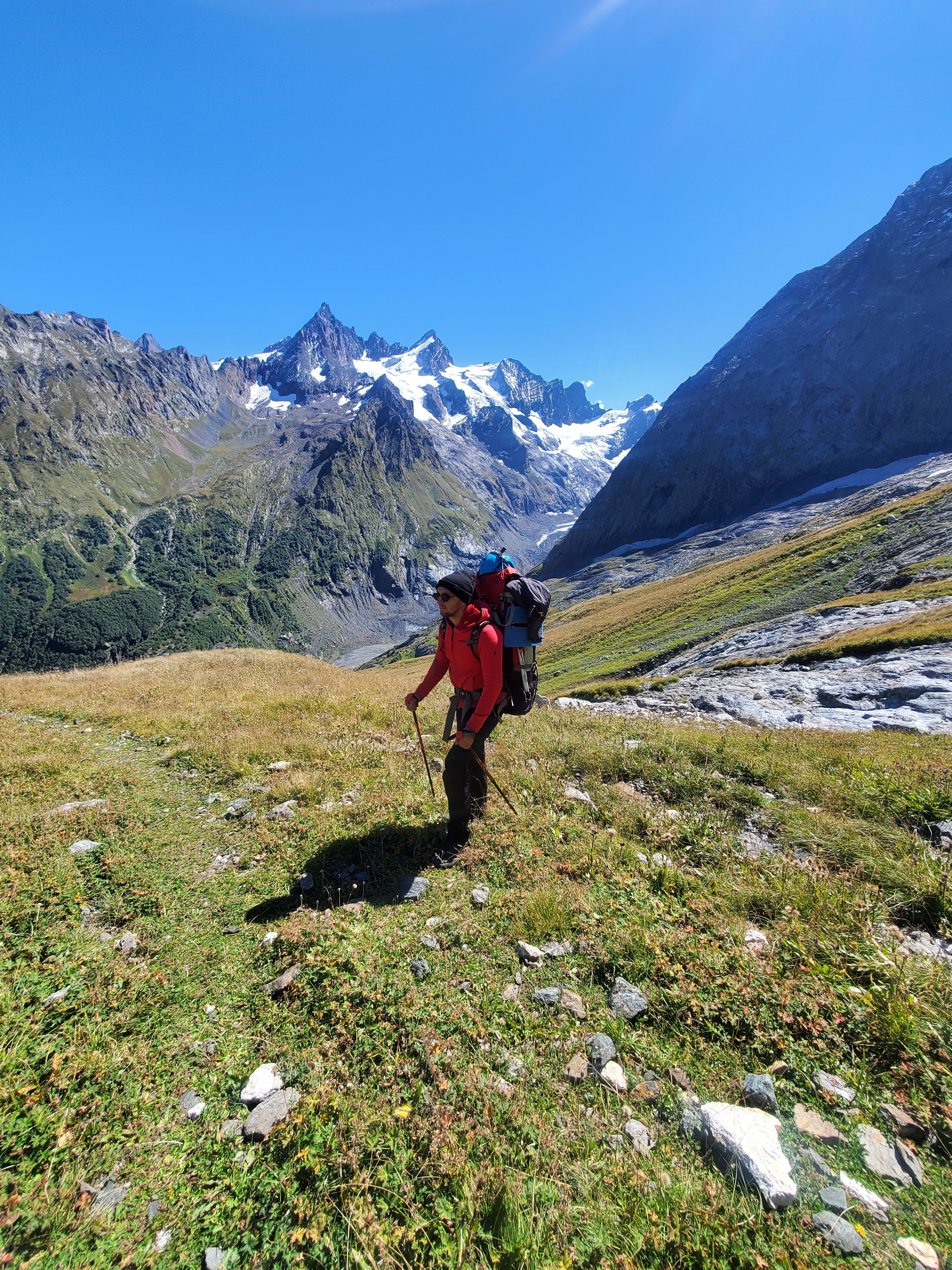 Man in Red Jacket and Black Pants Walking on Green Grass Field · Free ...