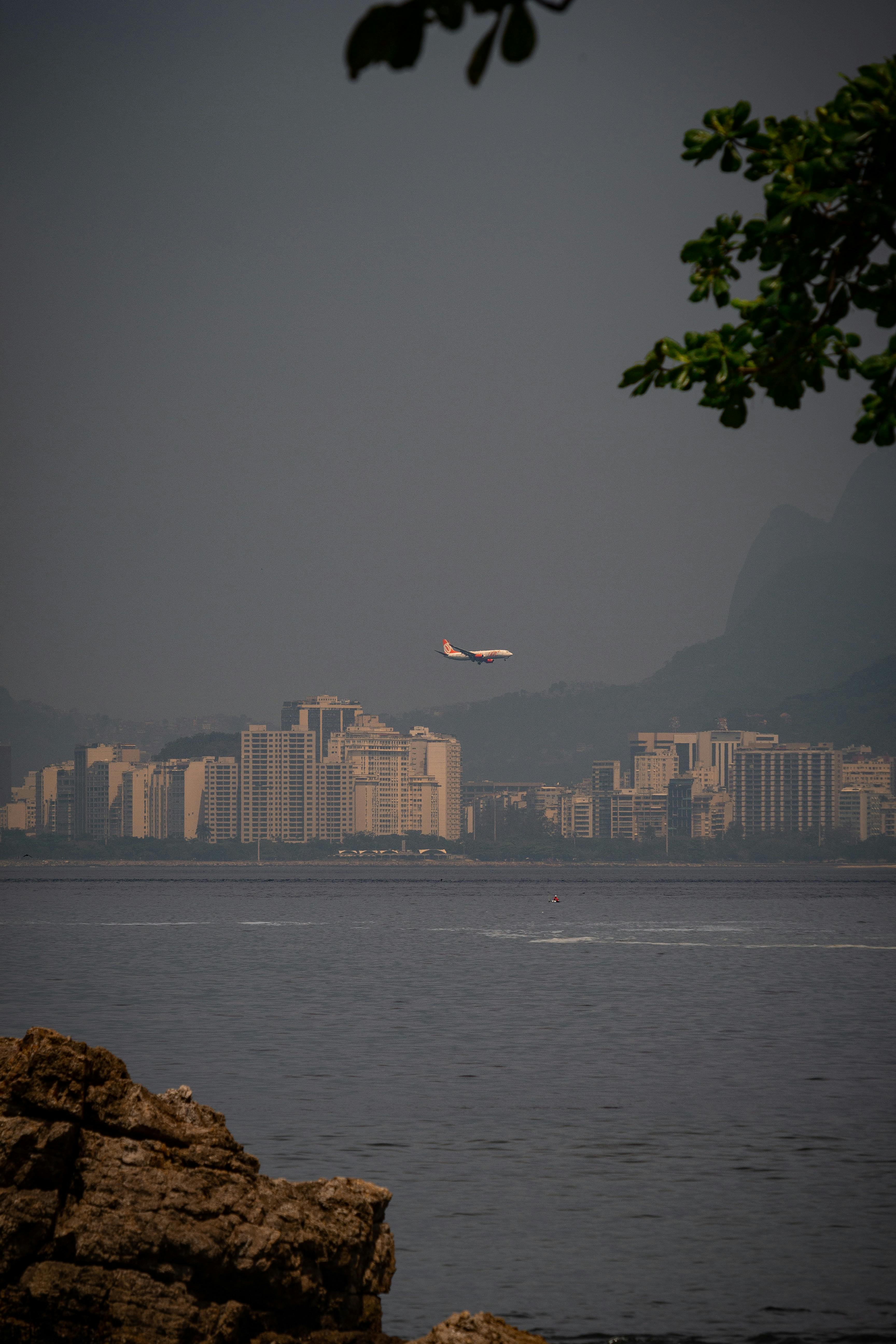 White Airplane Flying over White Concrete Buildings · Free Stock Photo